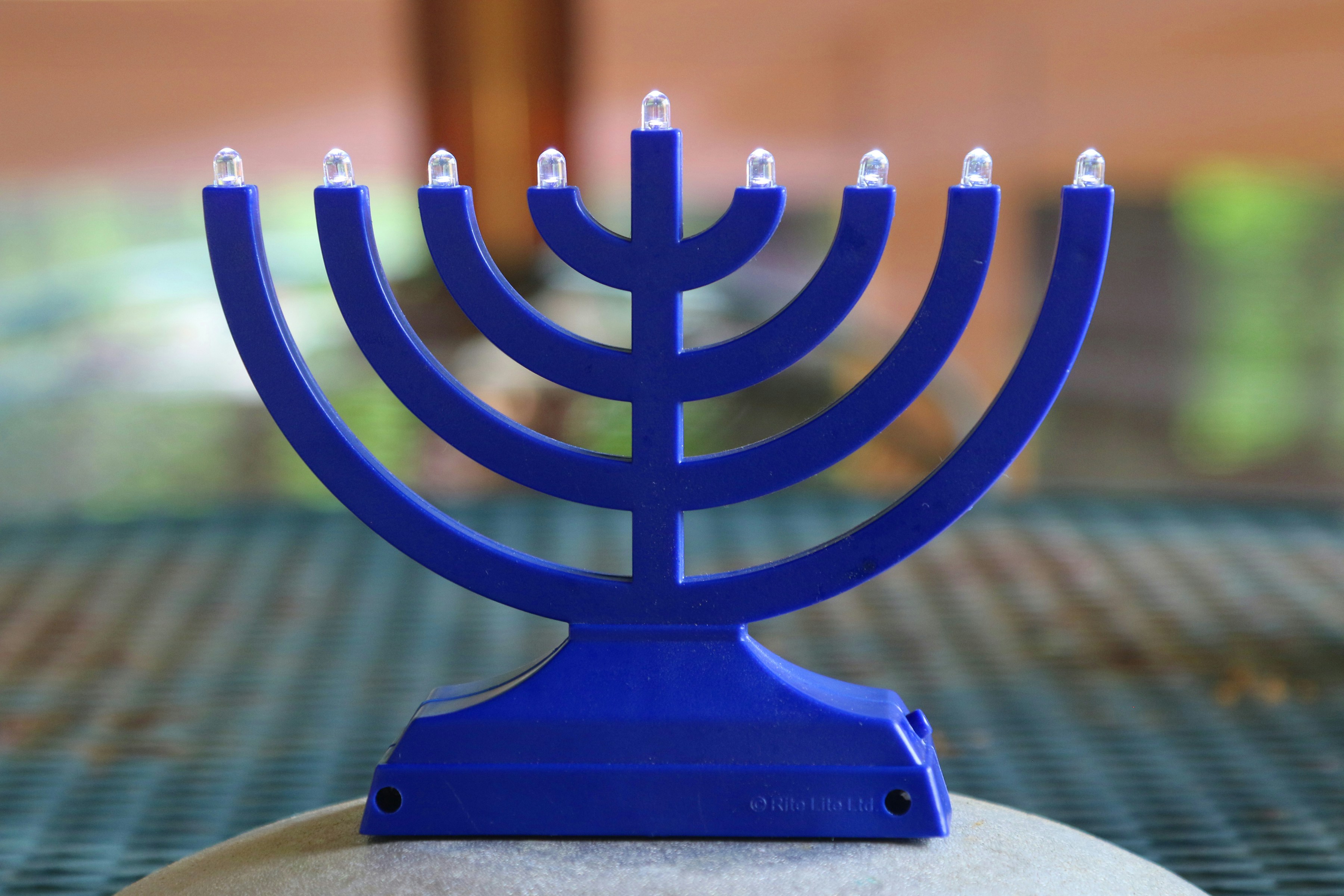 A vibrant blue menorah with LED lights stands on a smooth surface, symbolizing the Festival of Lights. Its elegant design contrasts against a softly blurred background.