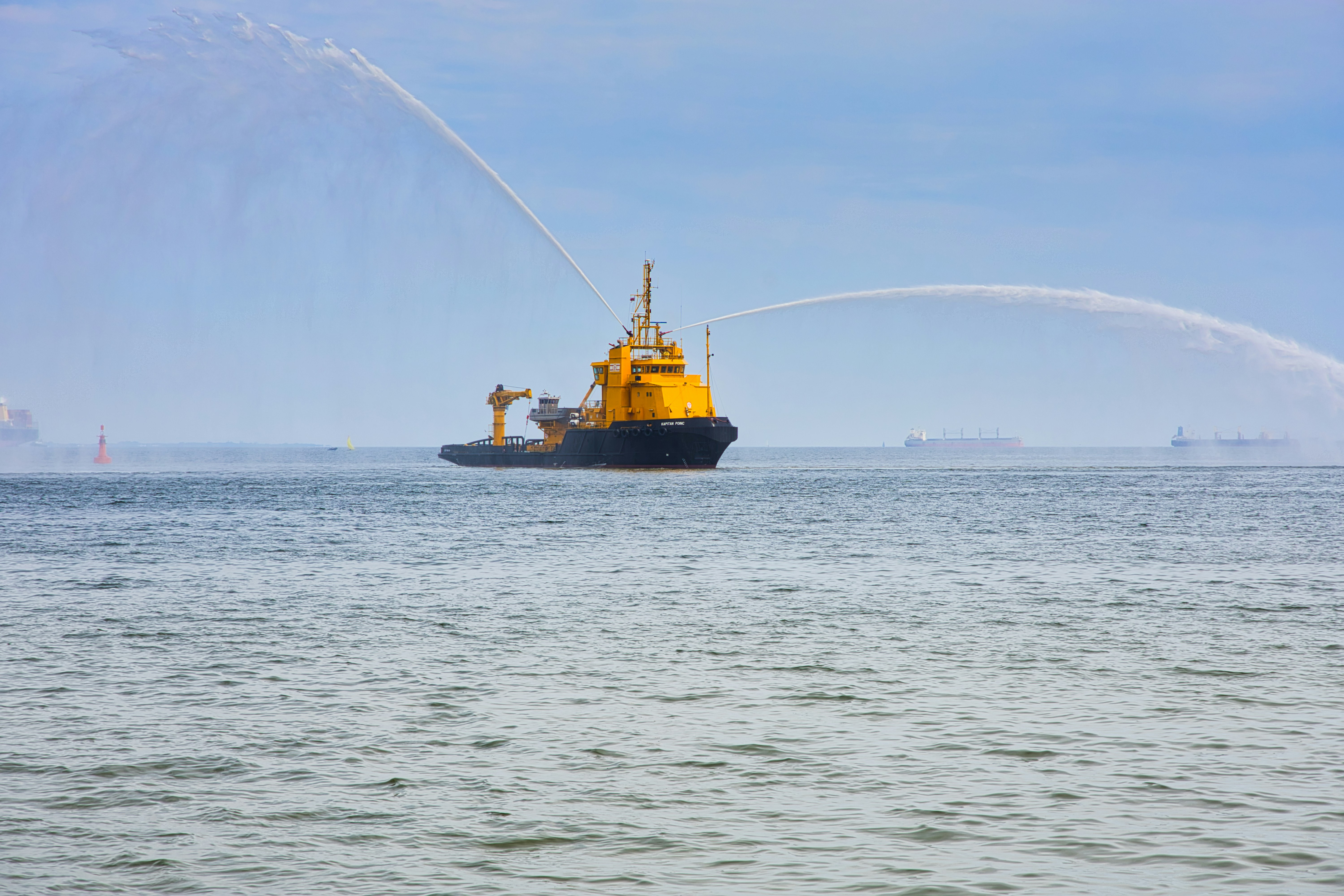 A large yellow boat spraying water on the ocean photo – Free Sea Image ...