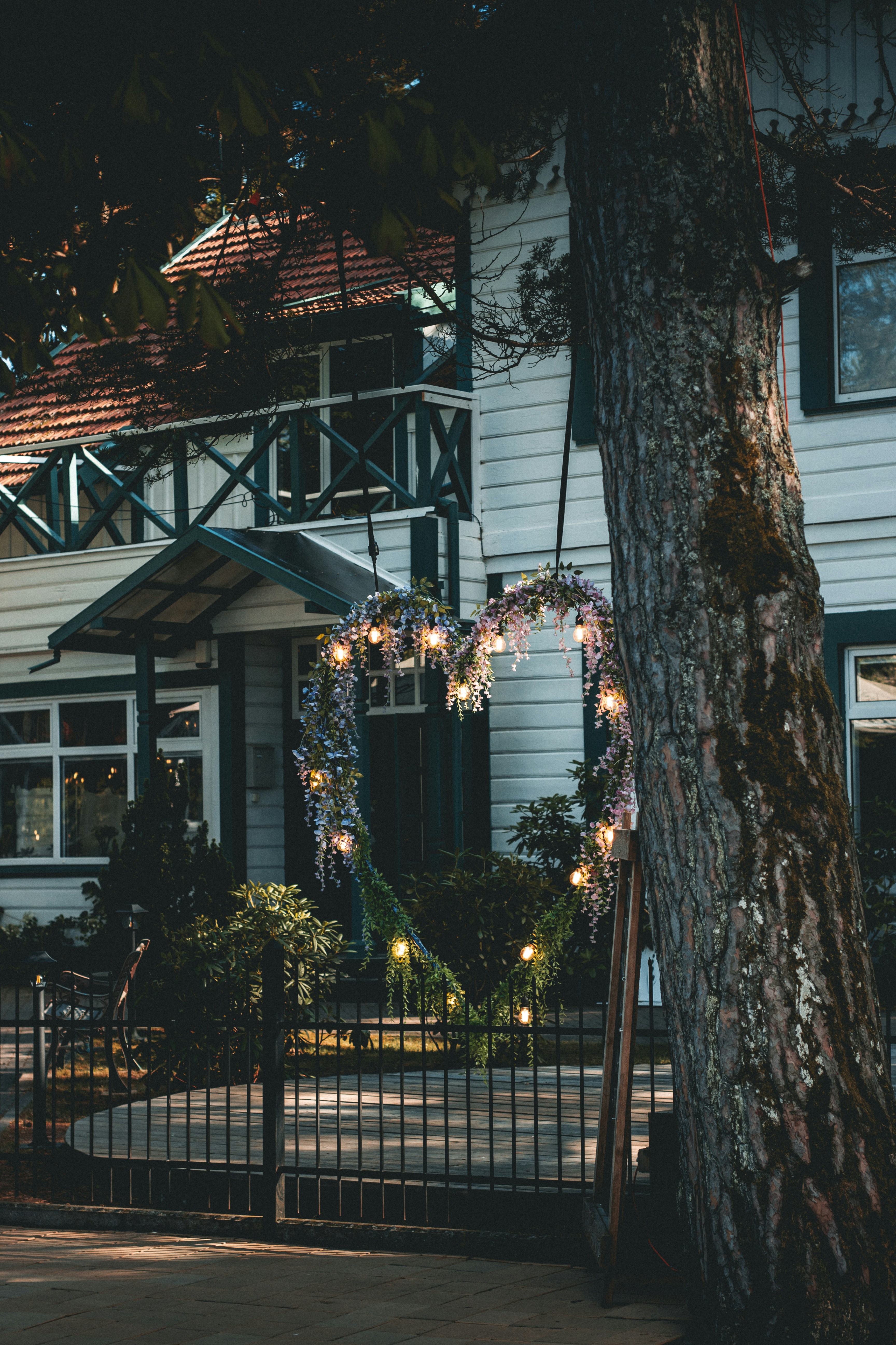 A white house with a black gate and a tree photo – Free Palanga Image ...