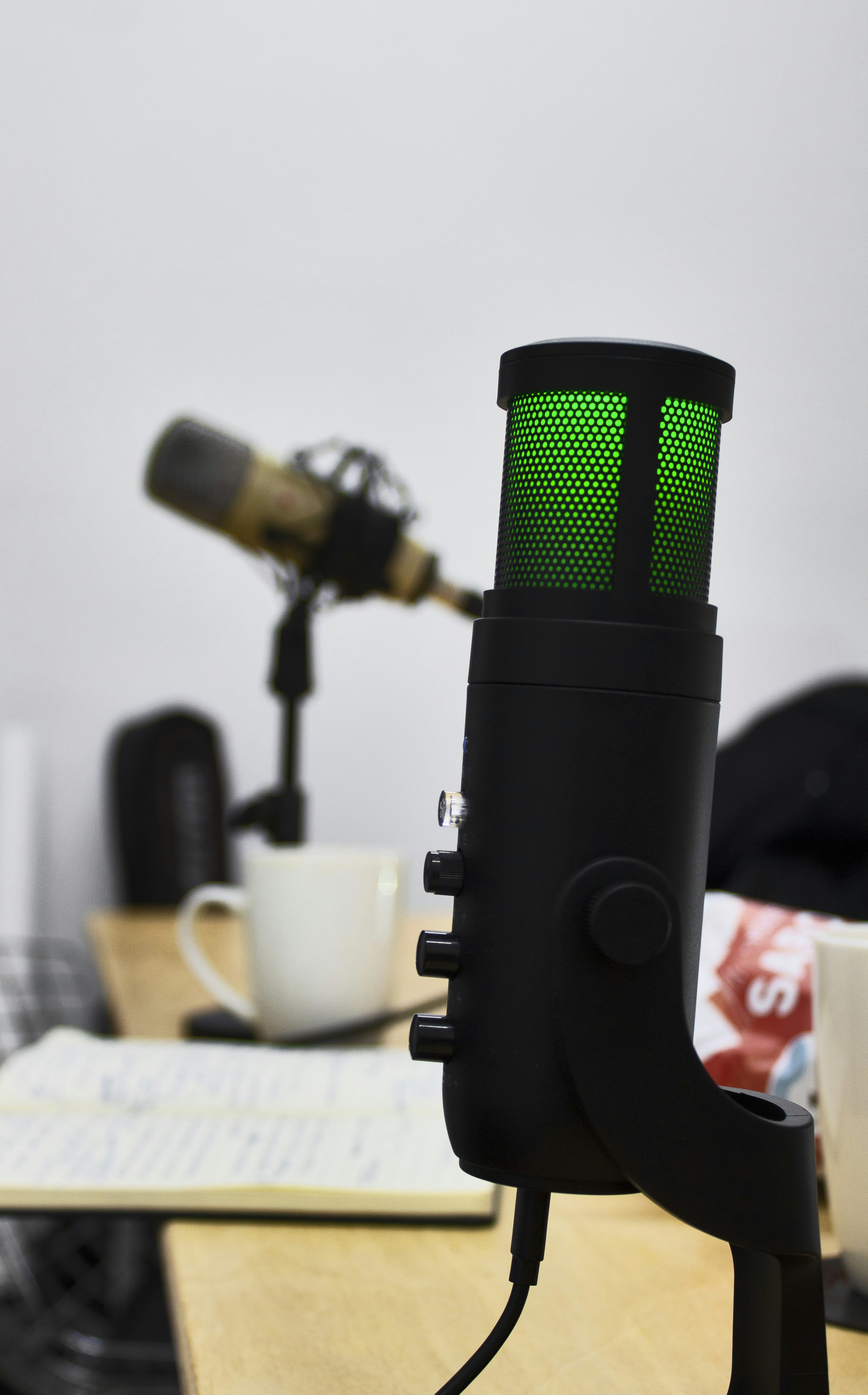 Emerald Mesh Sentinel: Close-Up of a Studio Microphone Dominating a Cluttered Desk