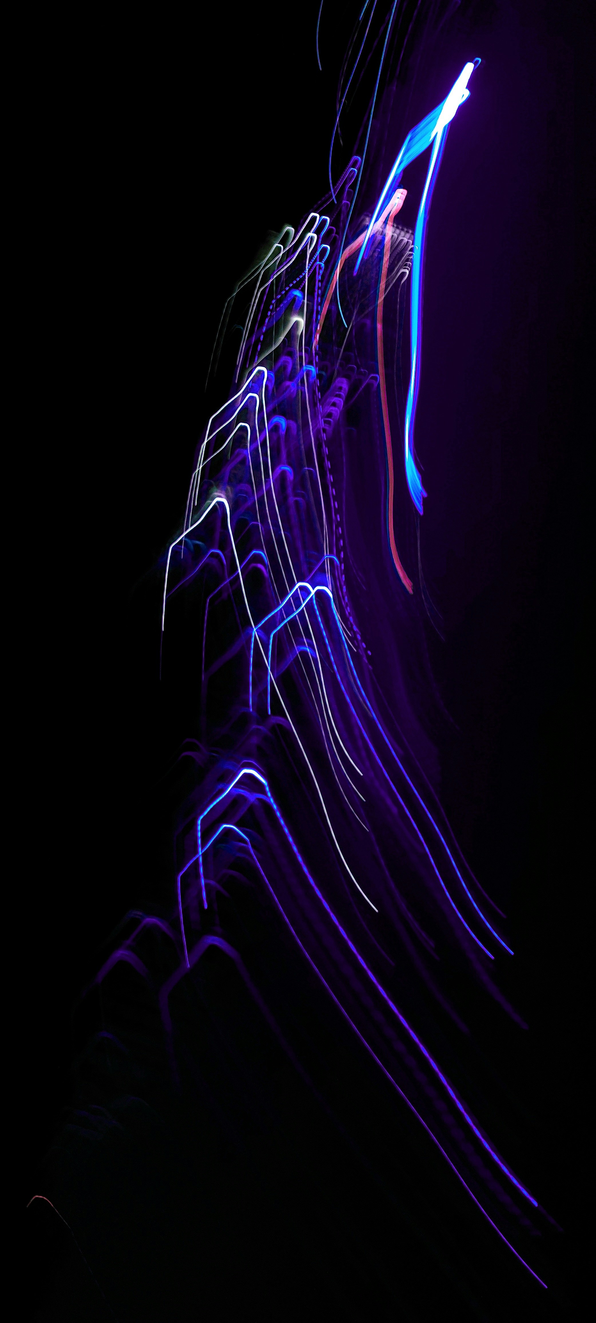 Long-exposure photograph capturing blue and violet light trails curving across a dark backdrop.
