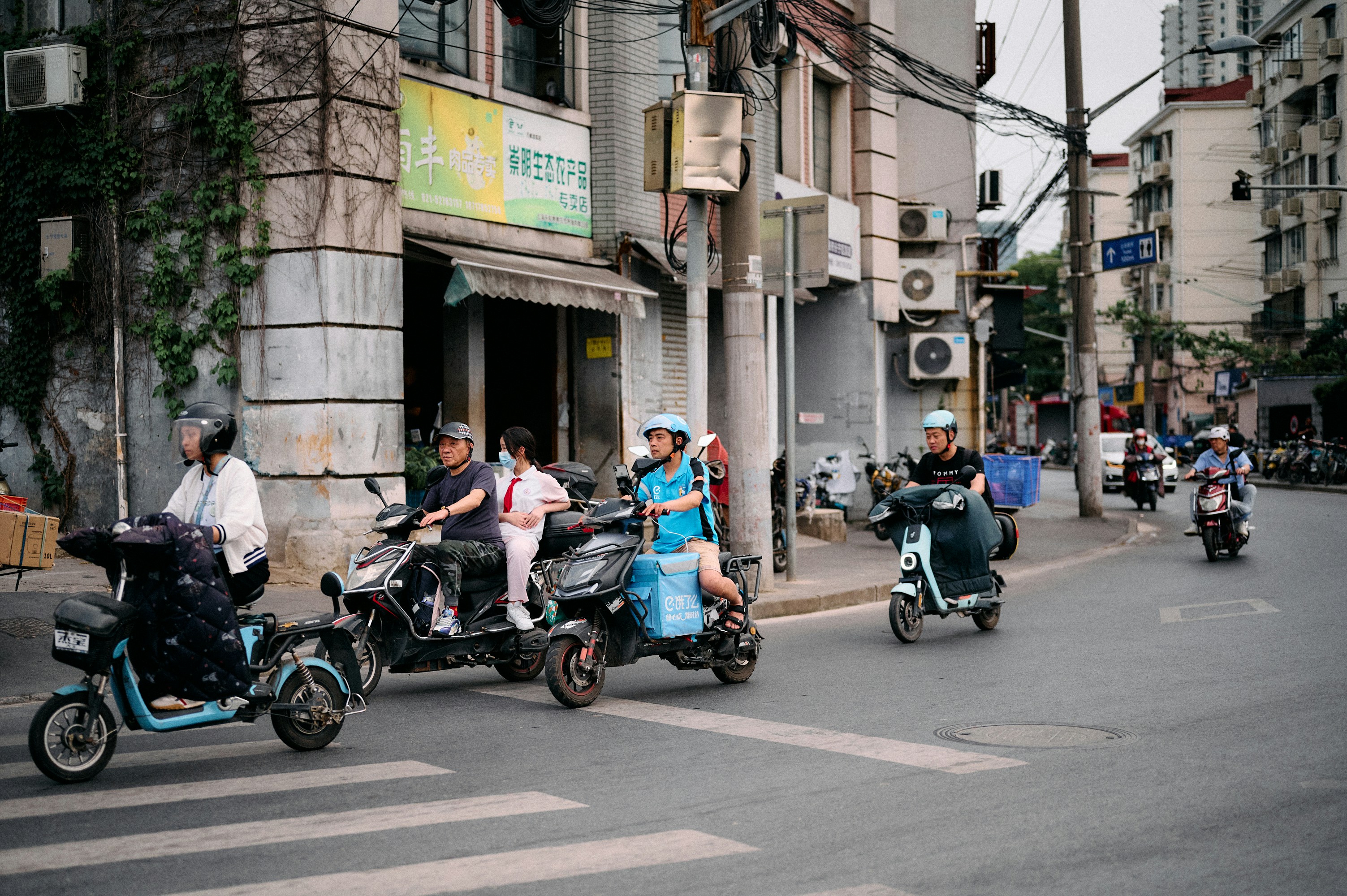 A group of people riding scooters down a street photo – Free Car Image ...