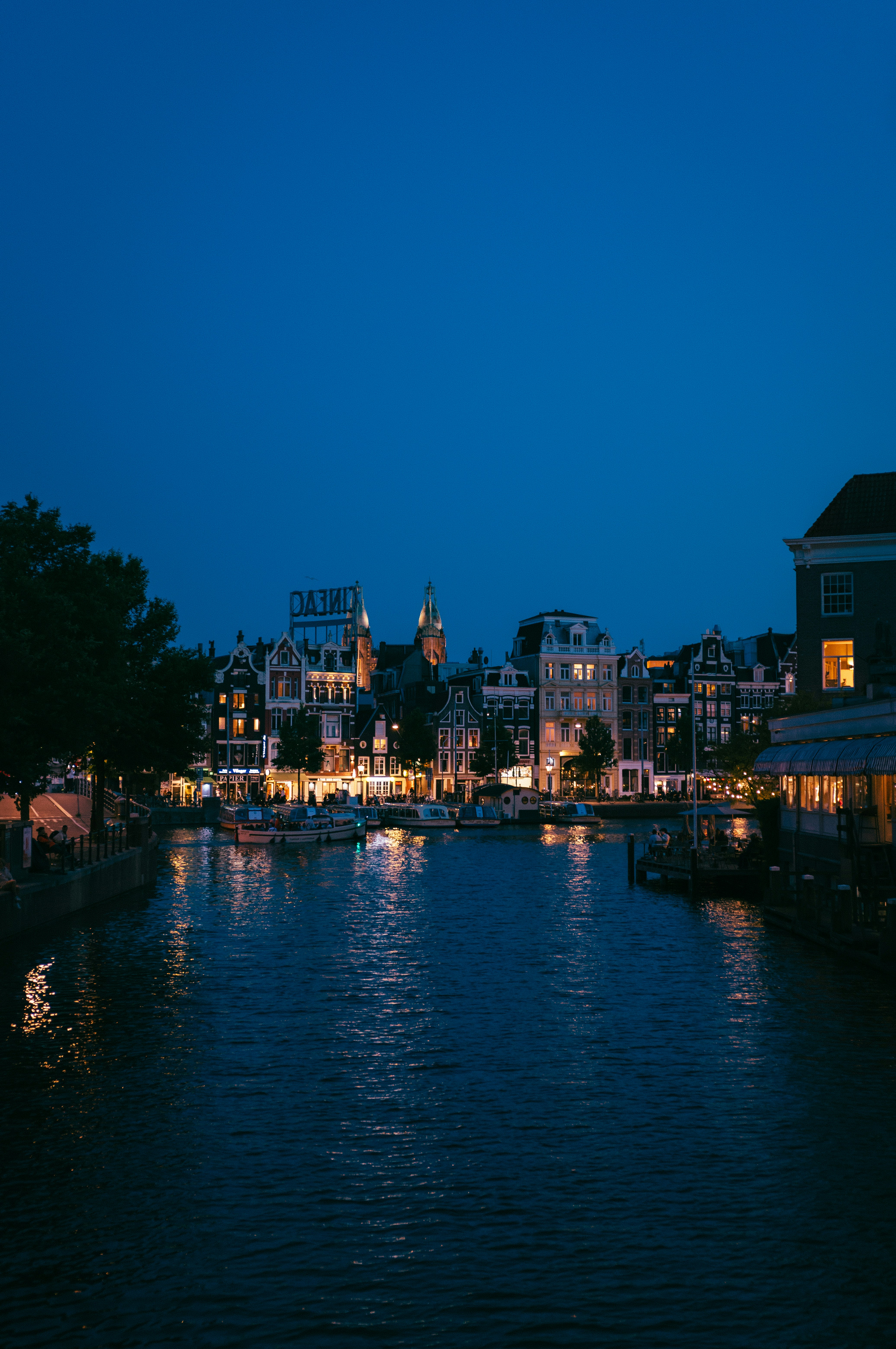 Evening view of a canal lined with softly lit buildings under a deep blue sky.
