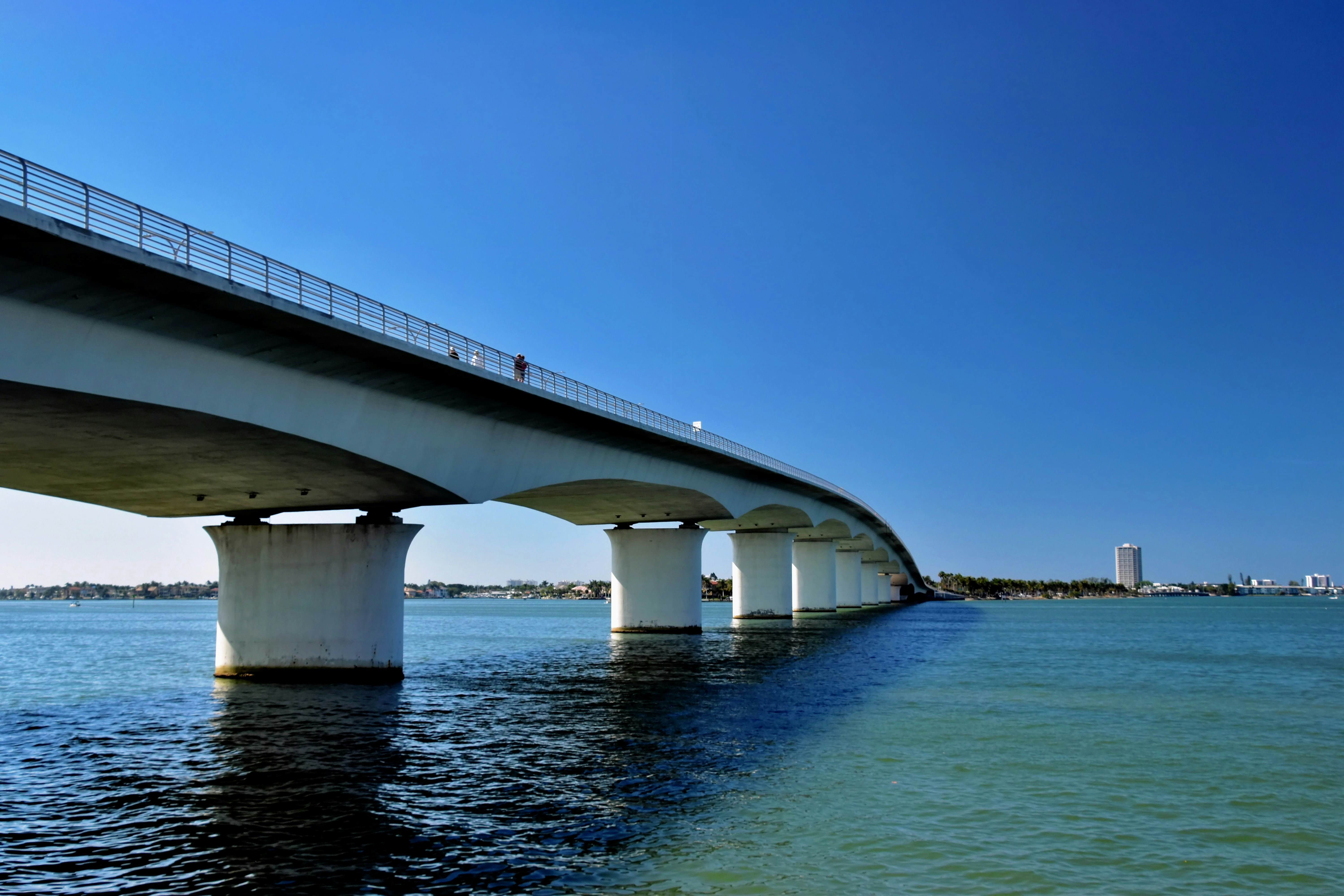 Elegant bridge stretching across tranquil blue waters under a clear sky.
