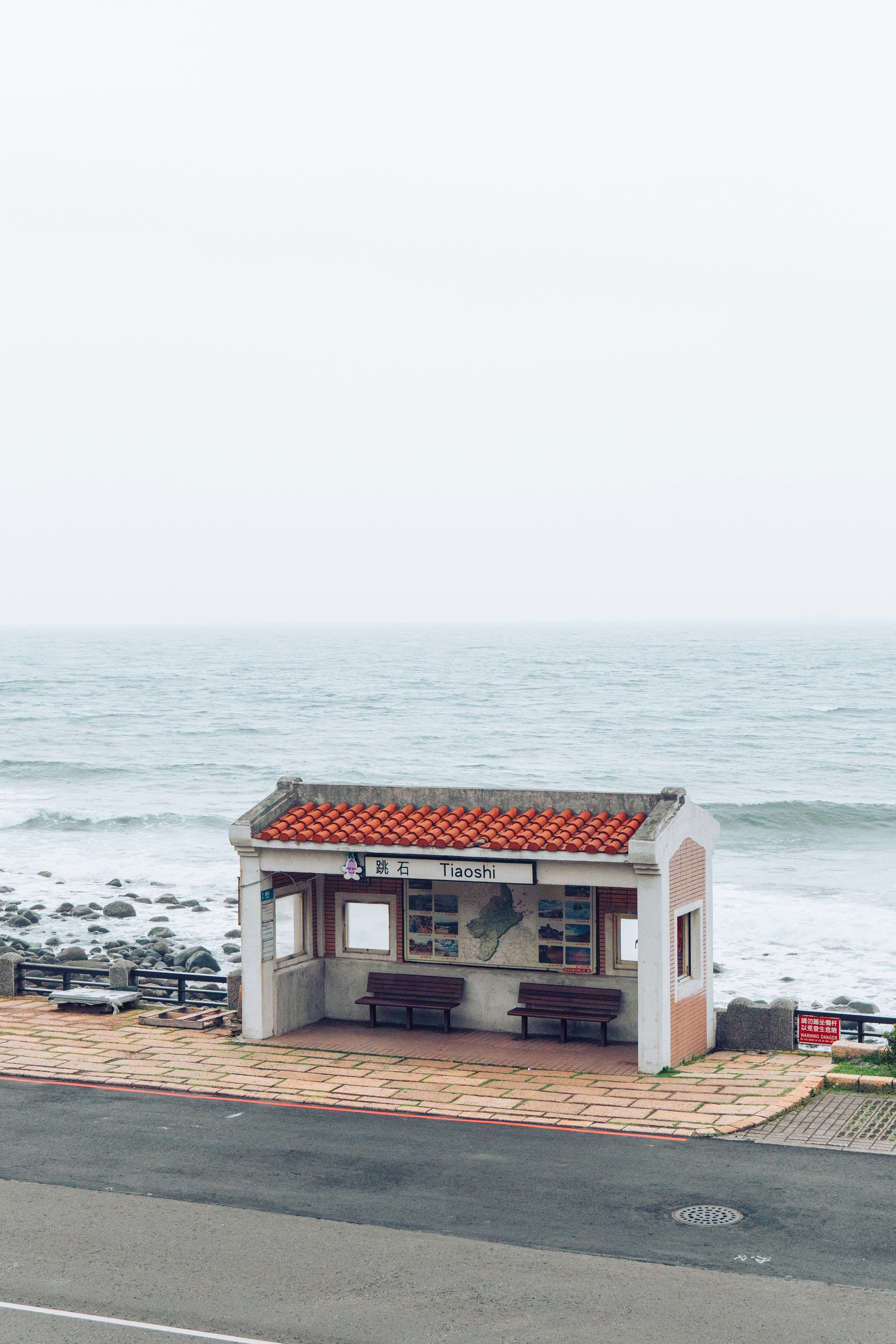 Red Roof Refuge by the Sea: A Seaside Bus Shelter Framed by Quiet Waves