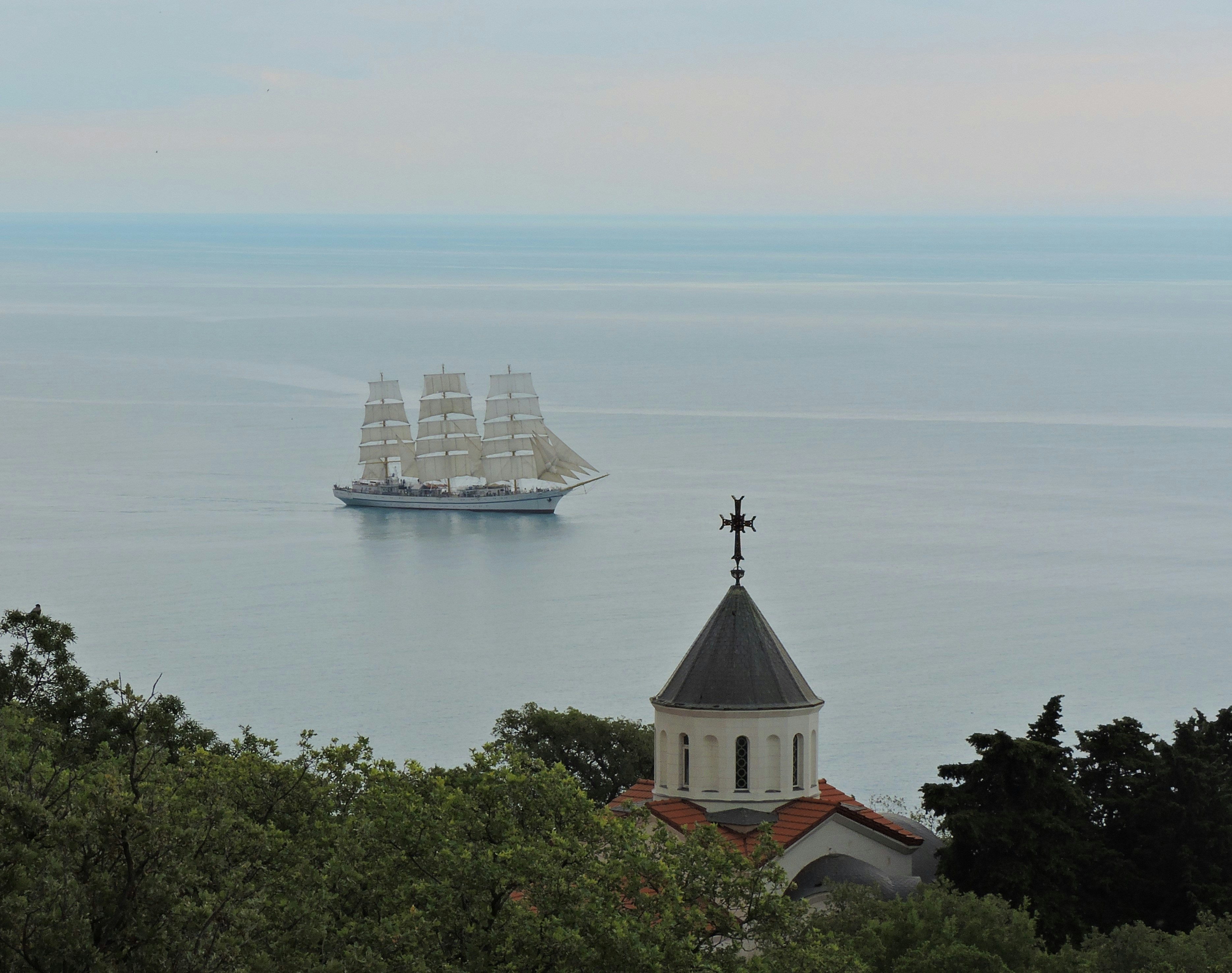 A sailboat sailing in the ocean near a church photo – Free Yalta Image ...