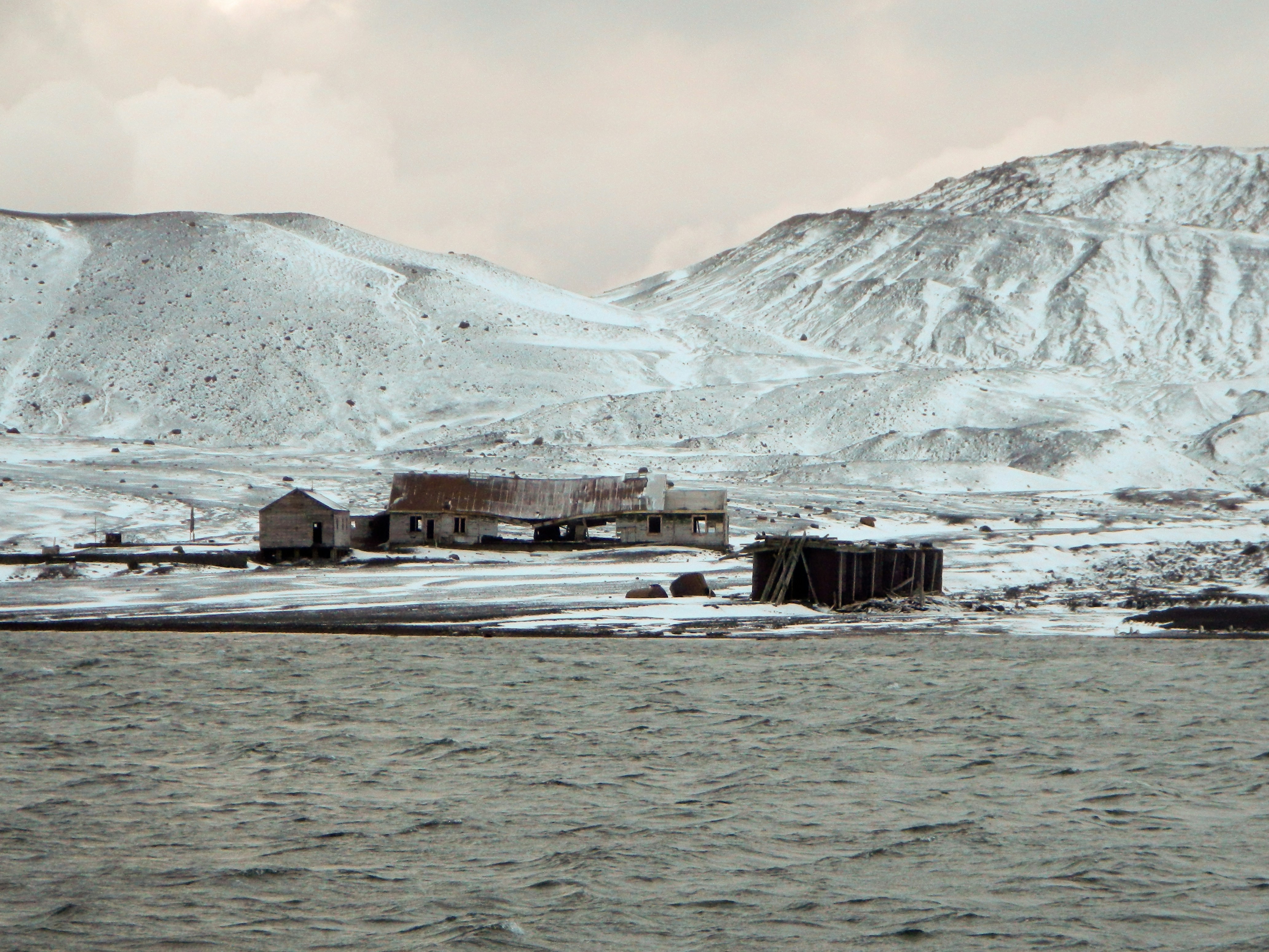 A snow covered mountain with a small shack in the foreground photo ...