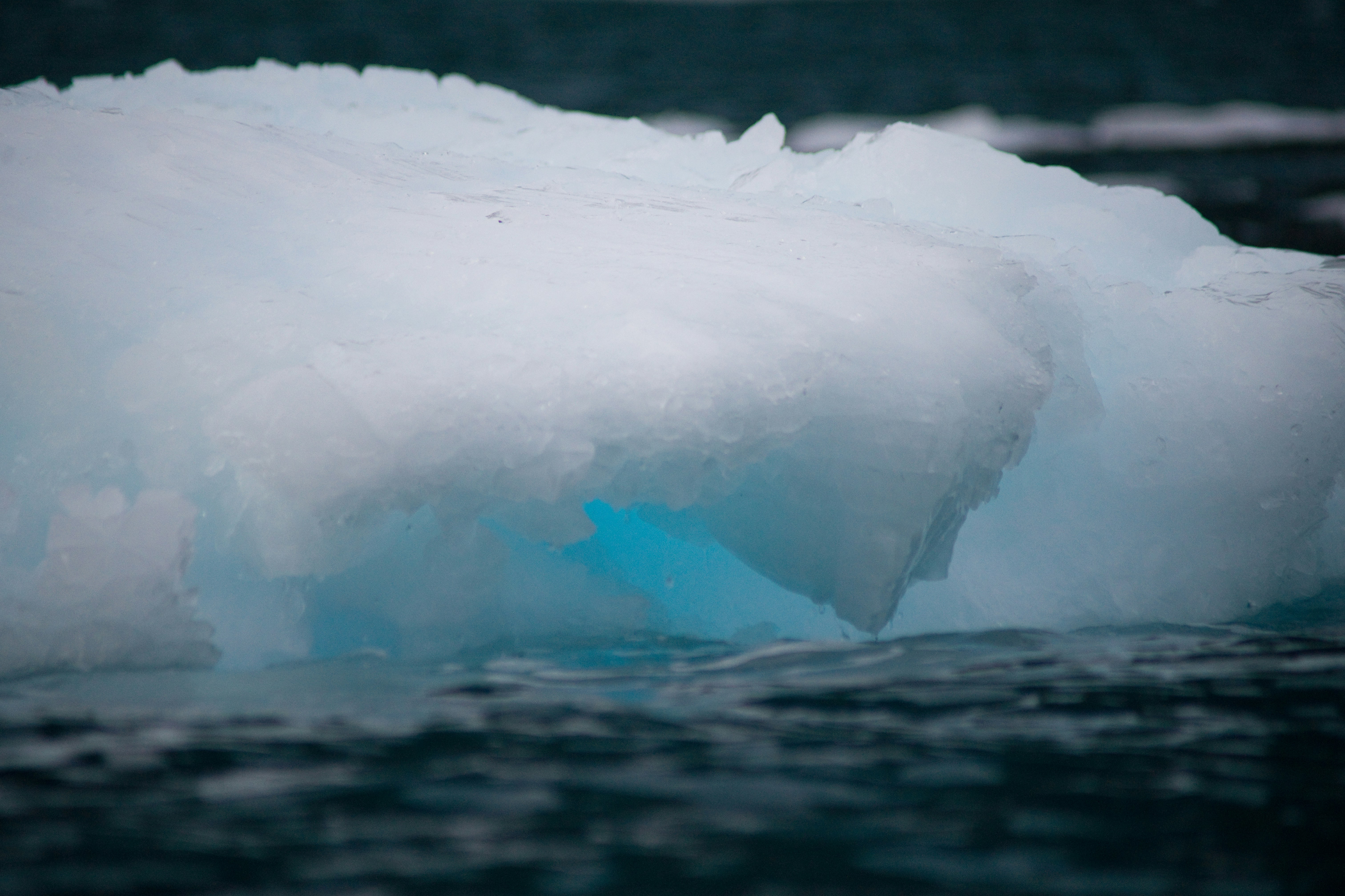 Blue-tinged Ice Edge Drifting Above Quiet Dark Water