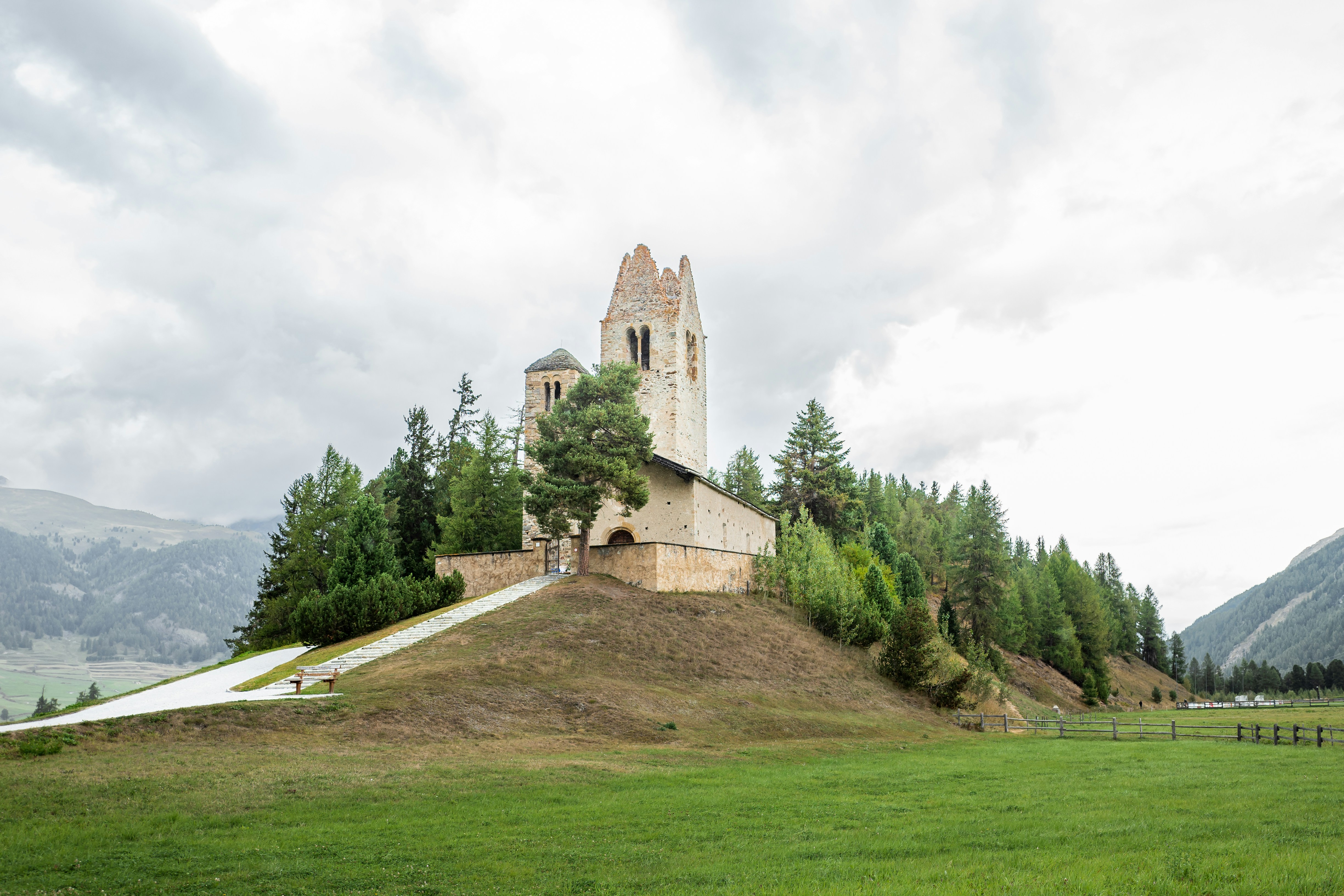 Stone Hilltop Ruin Surrounded by Pines under a Cloudy Sky