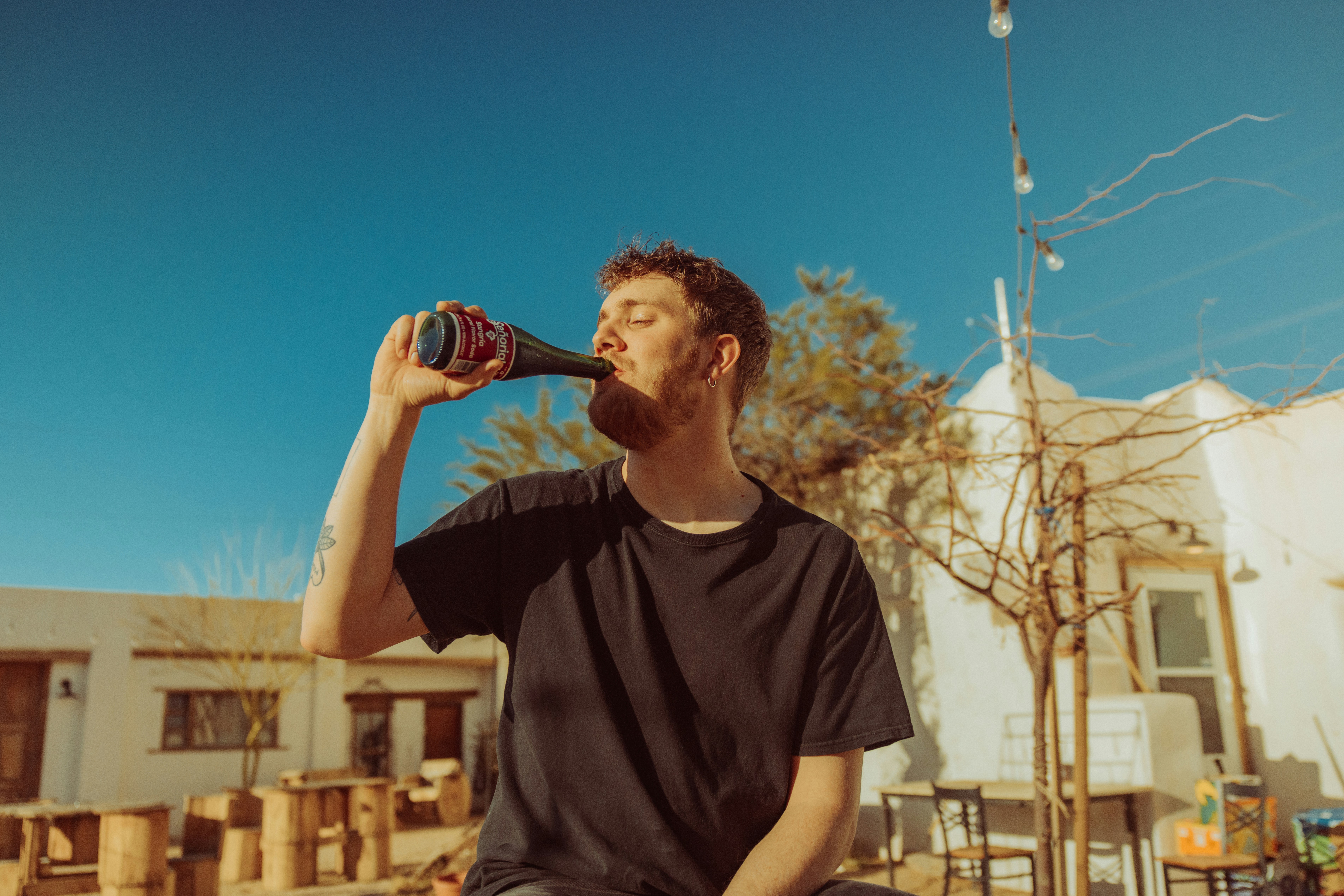 A man sitting on a bench drinking from a bottle photo – Free Dark Image ...