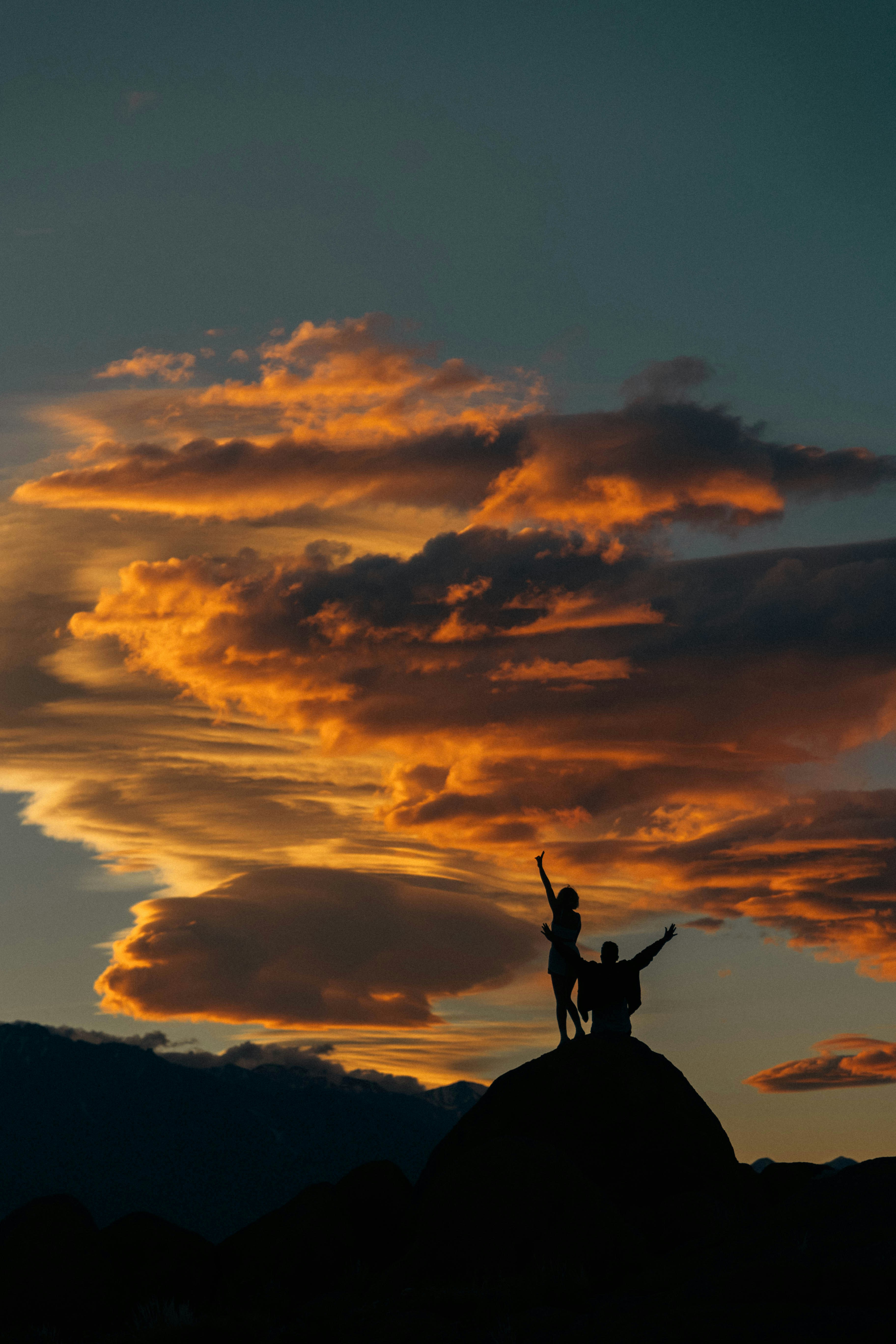 Crimson Cloudscape: Hands Aloft on the Cliff