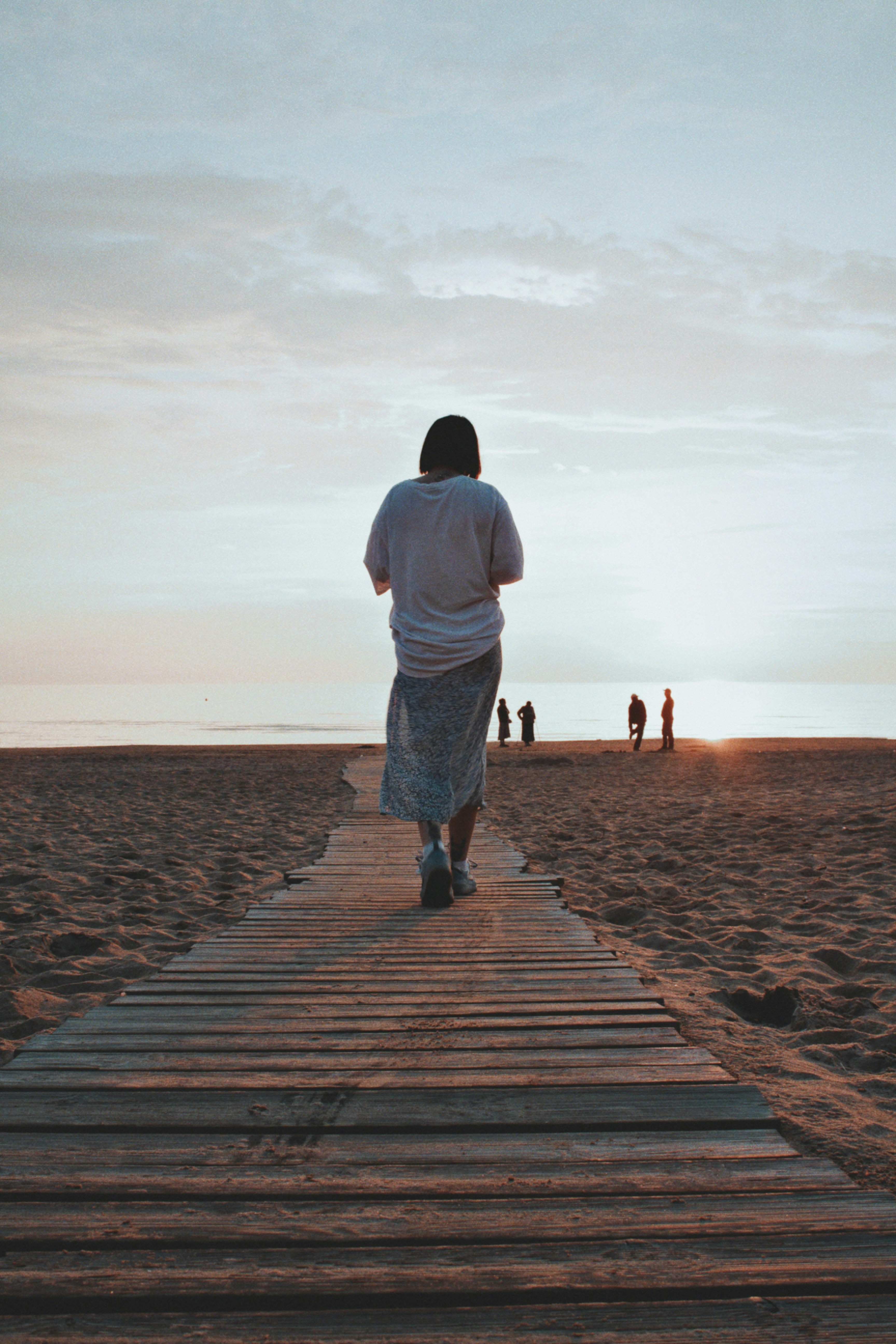 A person walking down a wooden walkway on a beach photo – Free Nature ...