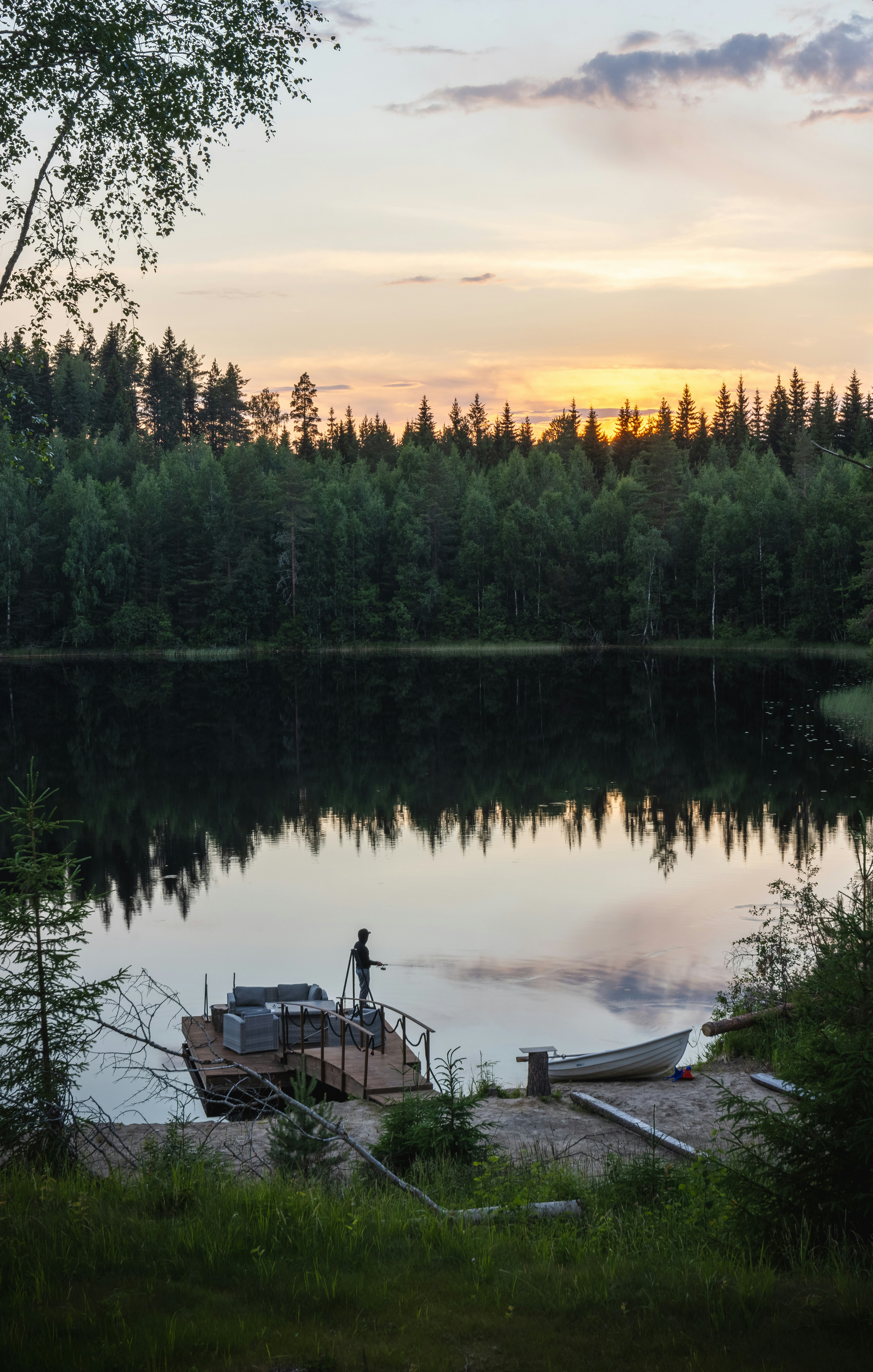 Dusk on the Dock: A solitary fisherman by a glassy lake