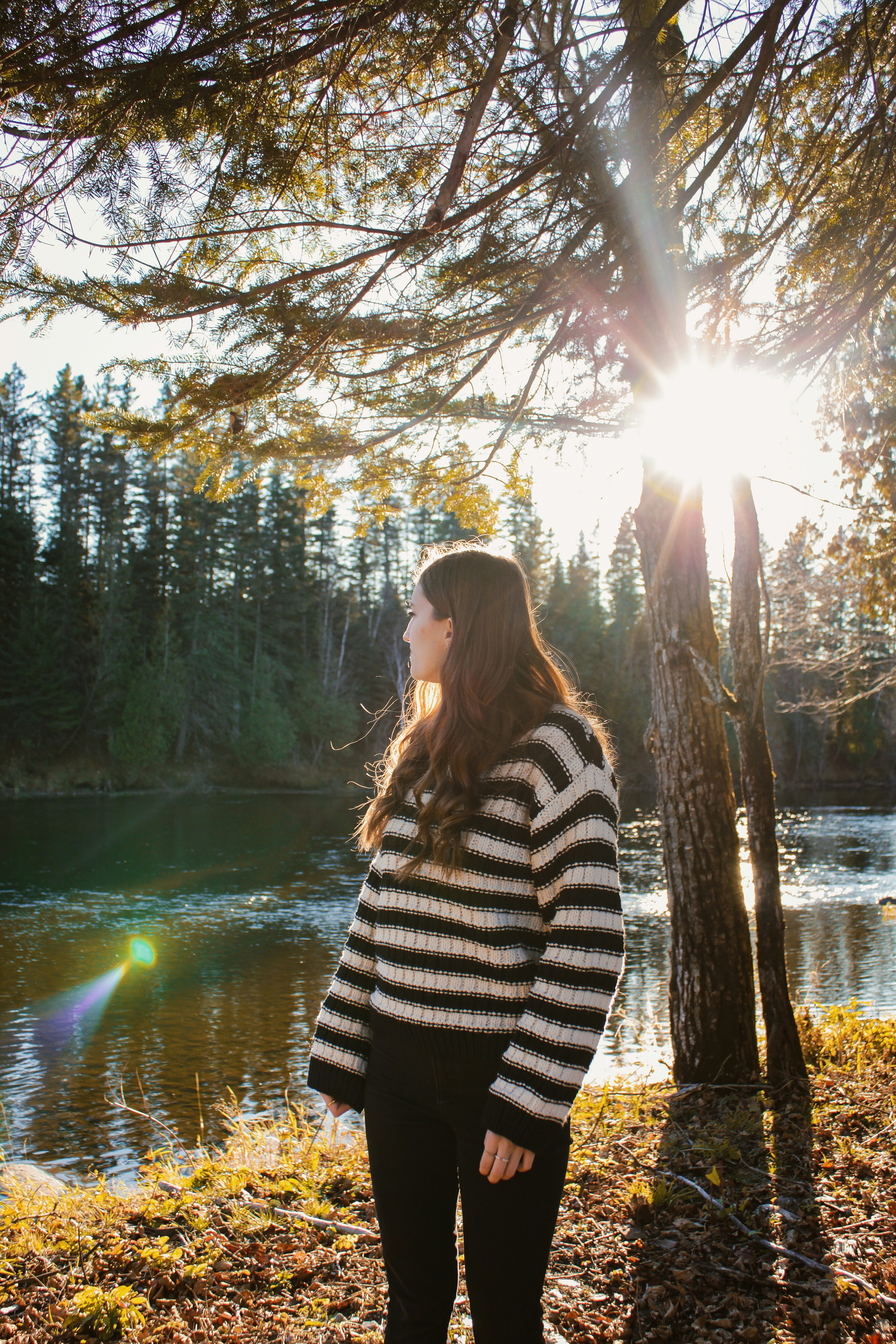 Sunlit Portrait by the Lake: Striped Knit Amid Autumn Pines