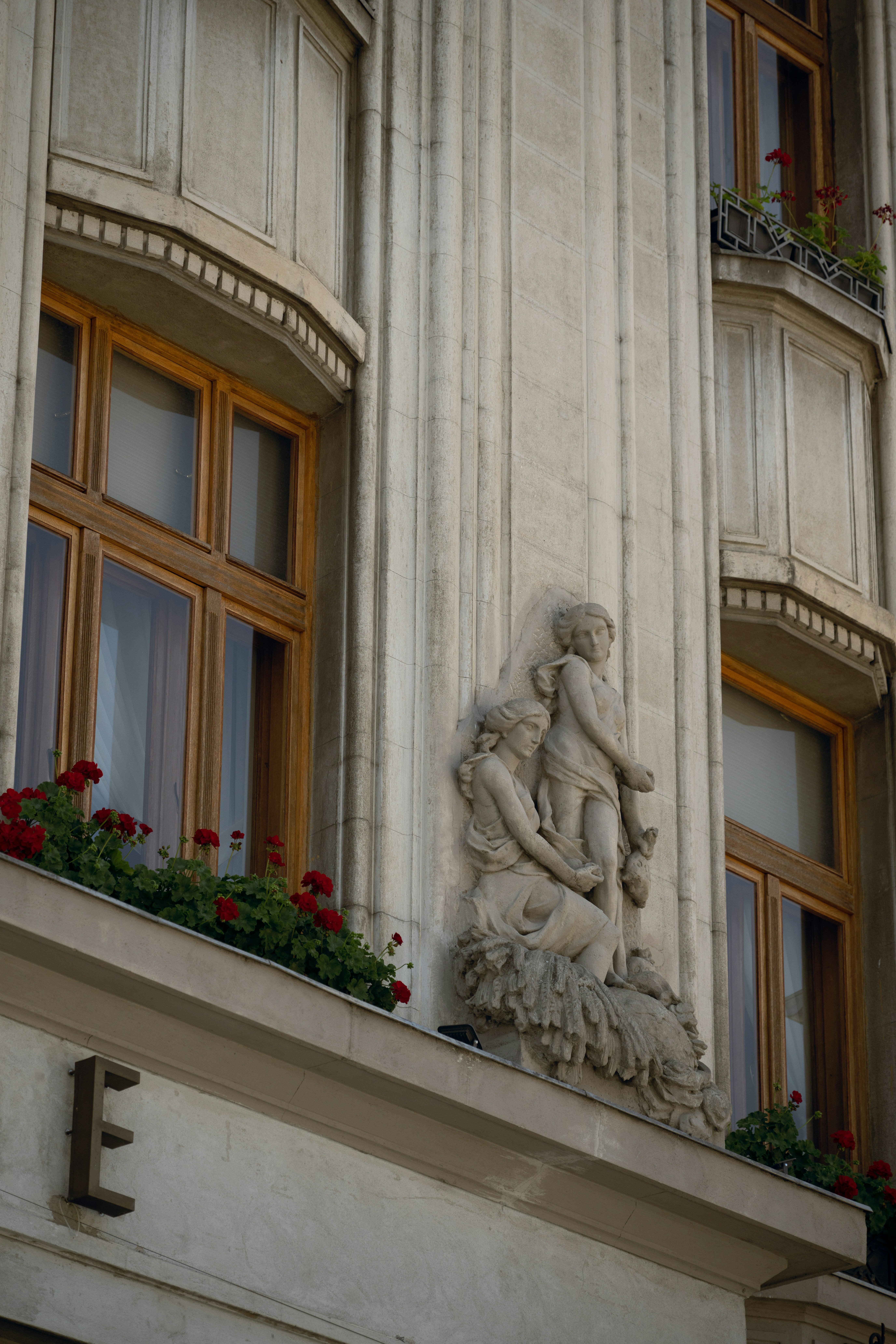 Ornate Facade Sculpture Framed by Windowed Carvings and Red Geraniums