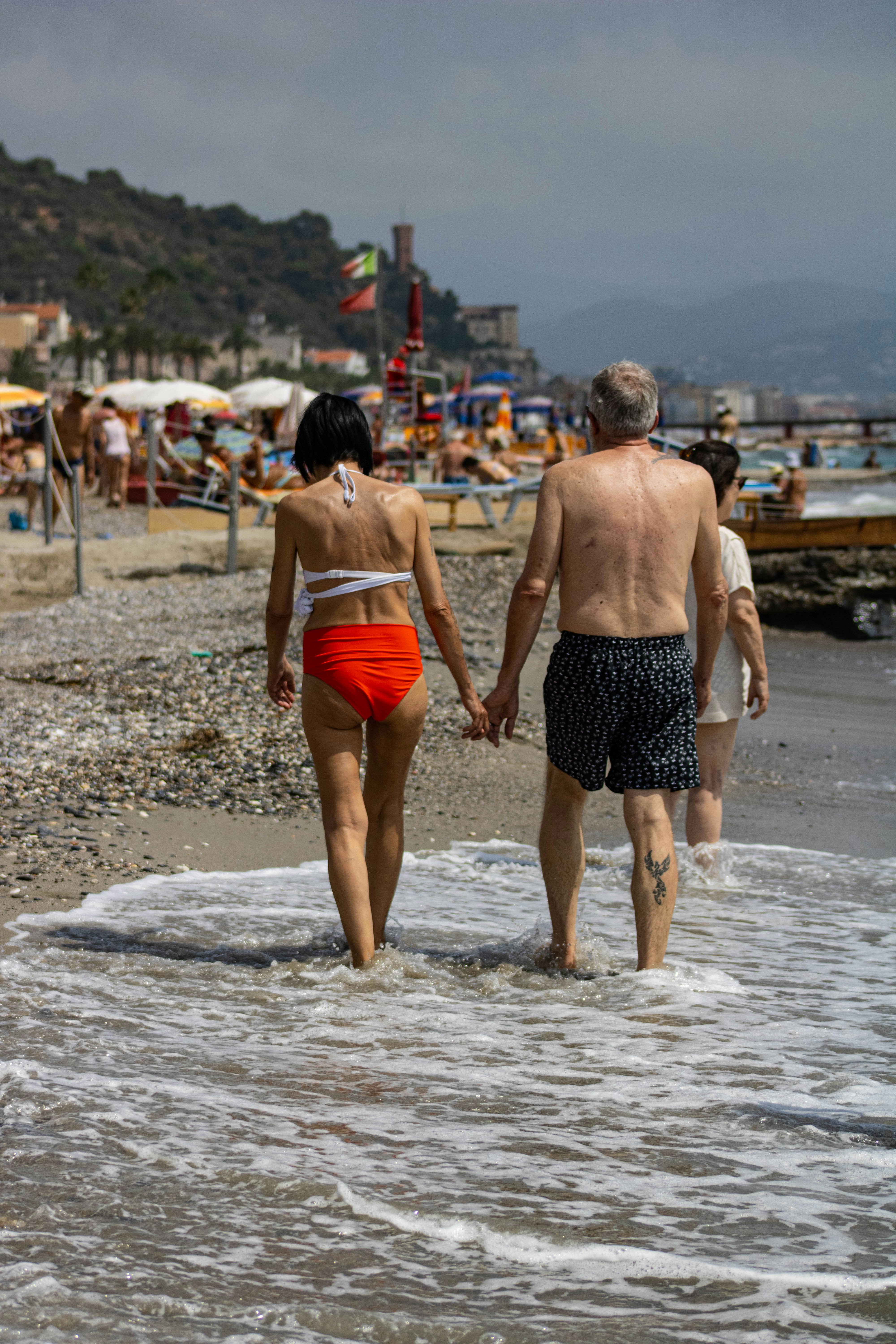 Couple Clocking in: Hand in Hand on a Shallow Beach Walk