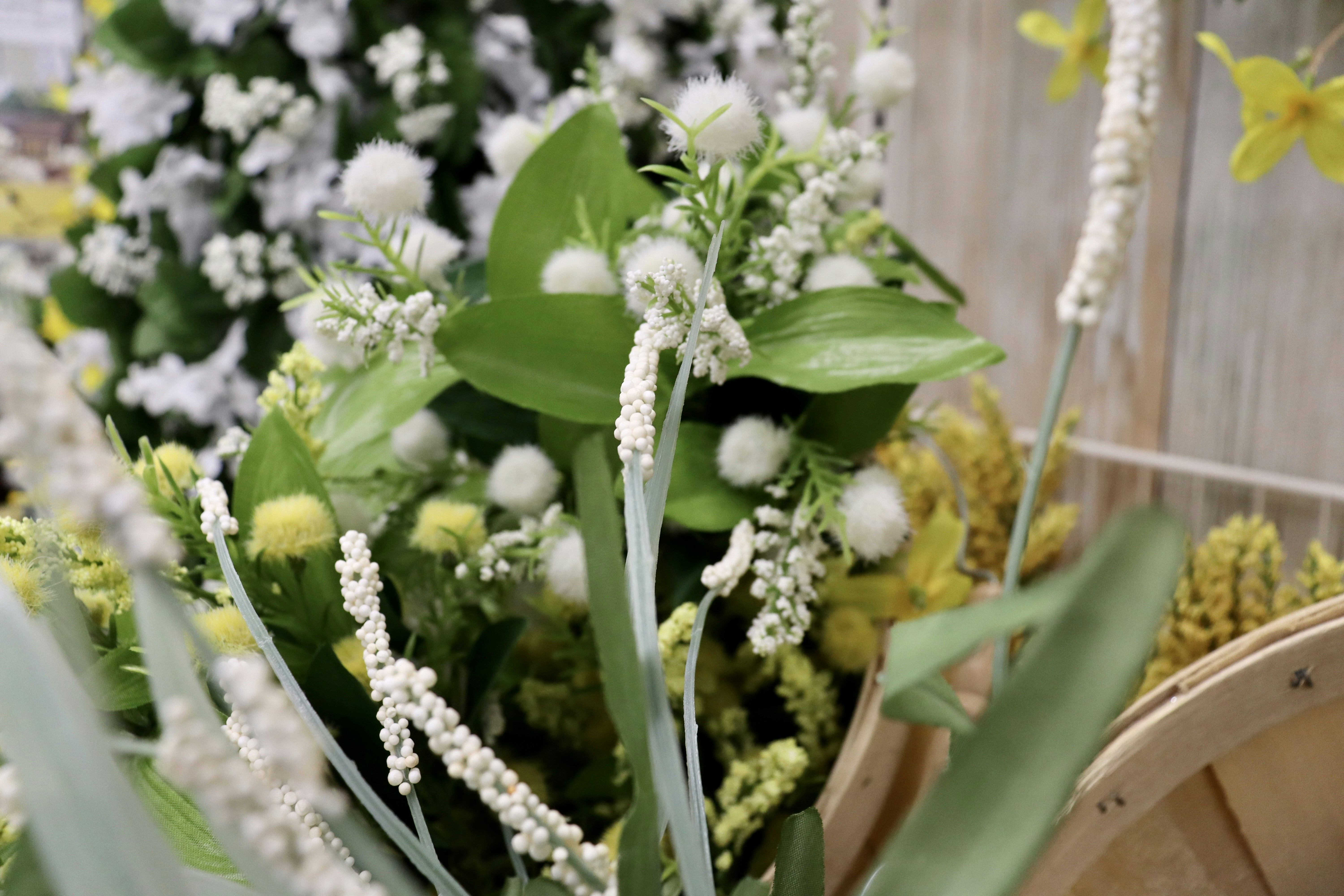 White Pompon Florals Framed by Greenery in a Rustic Basket