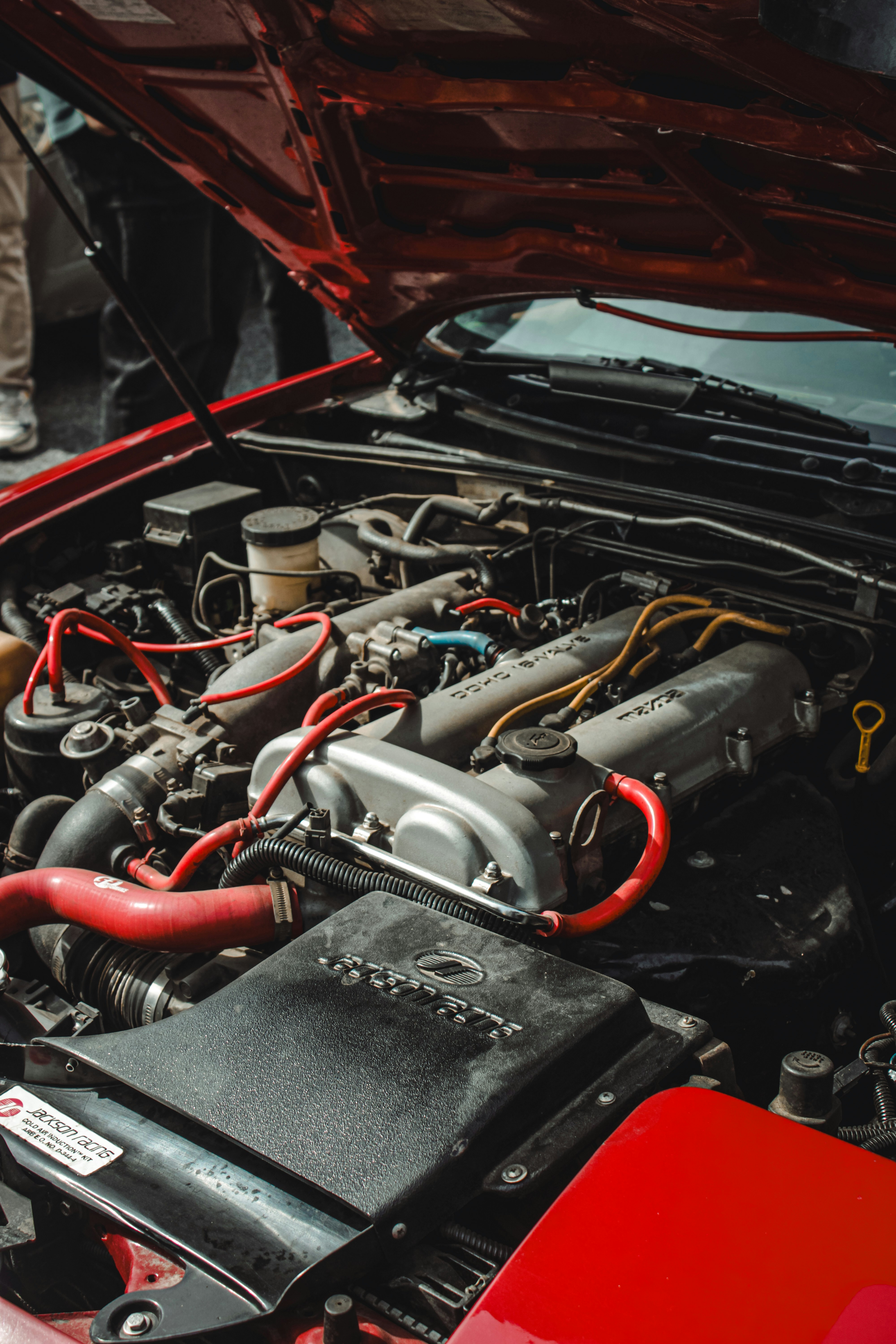 The engine of a red car with its hood open photo – Free Car engine ...