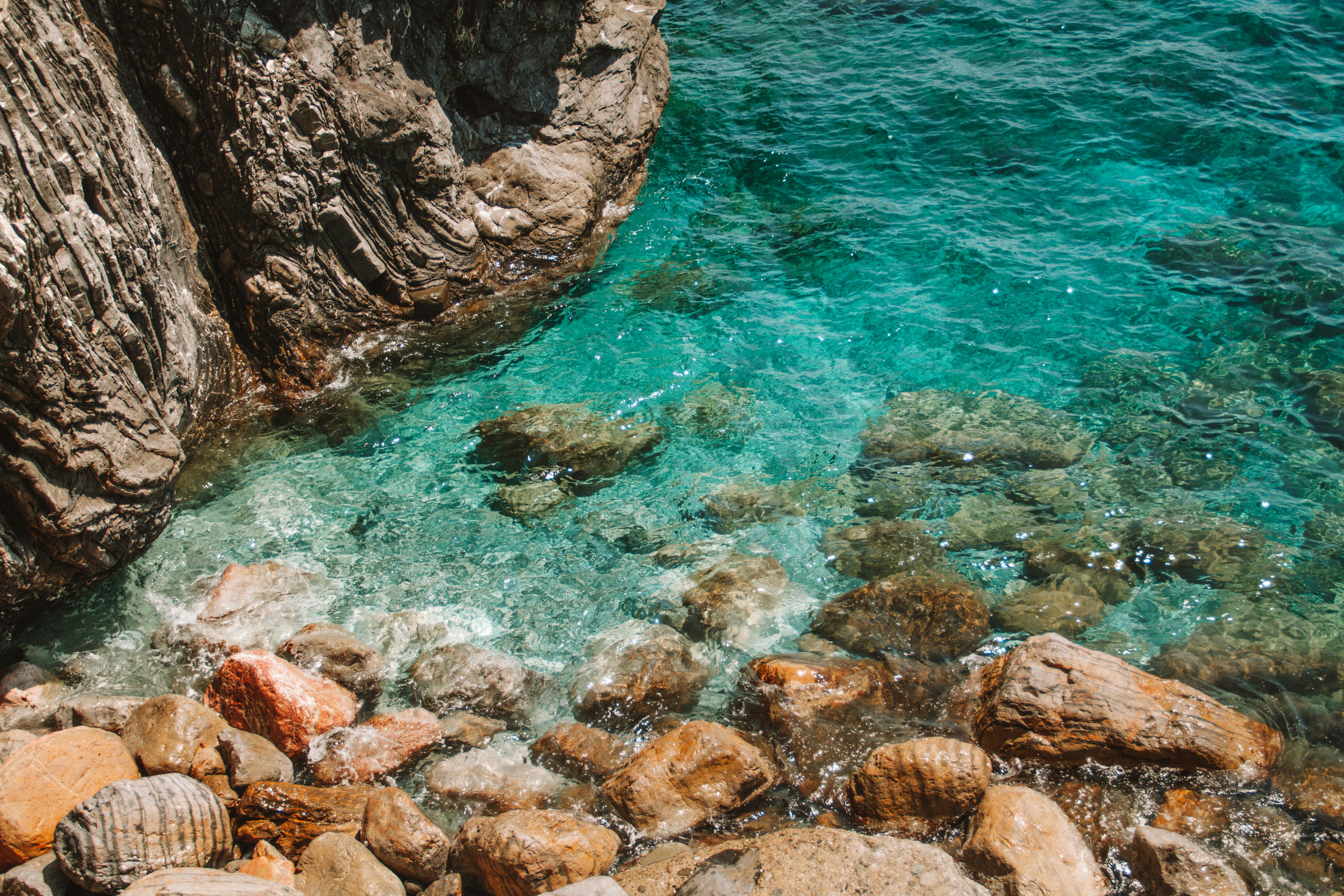 A body of water surrounded by rocks and a cliff photo – Free Woman ...