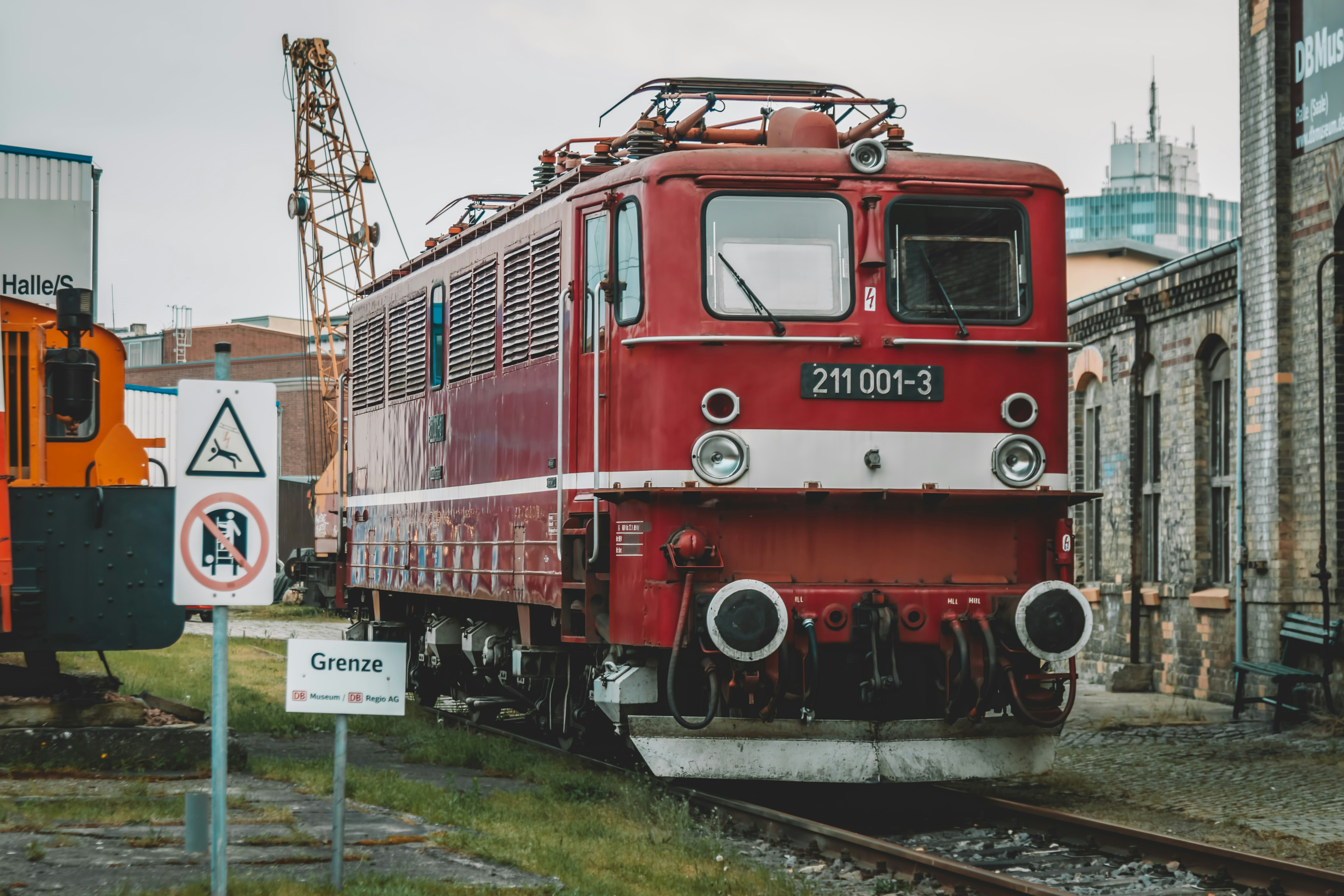Crimson Locomotive Amid Industrial Rails and Crane Shadows