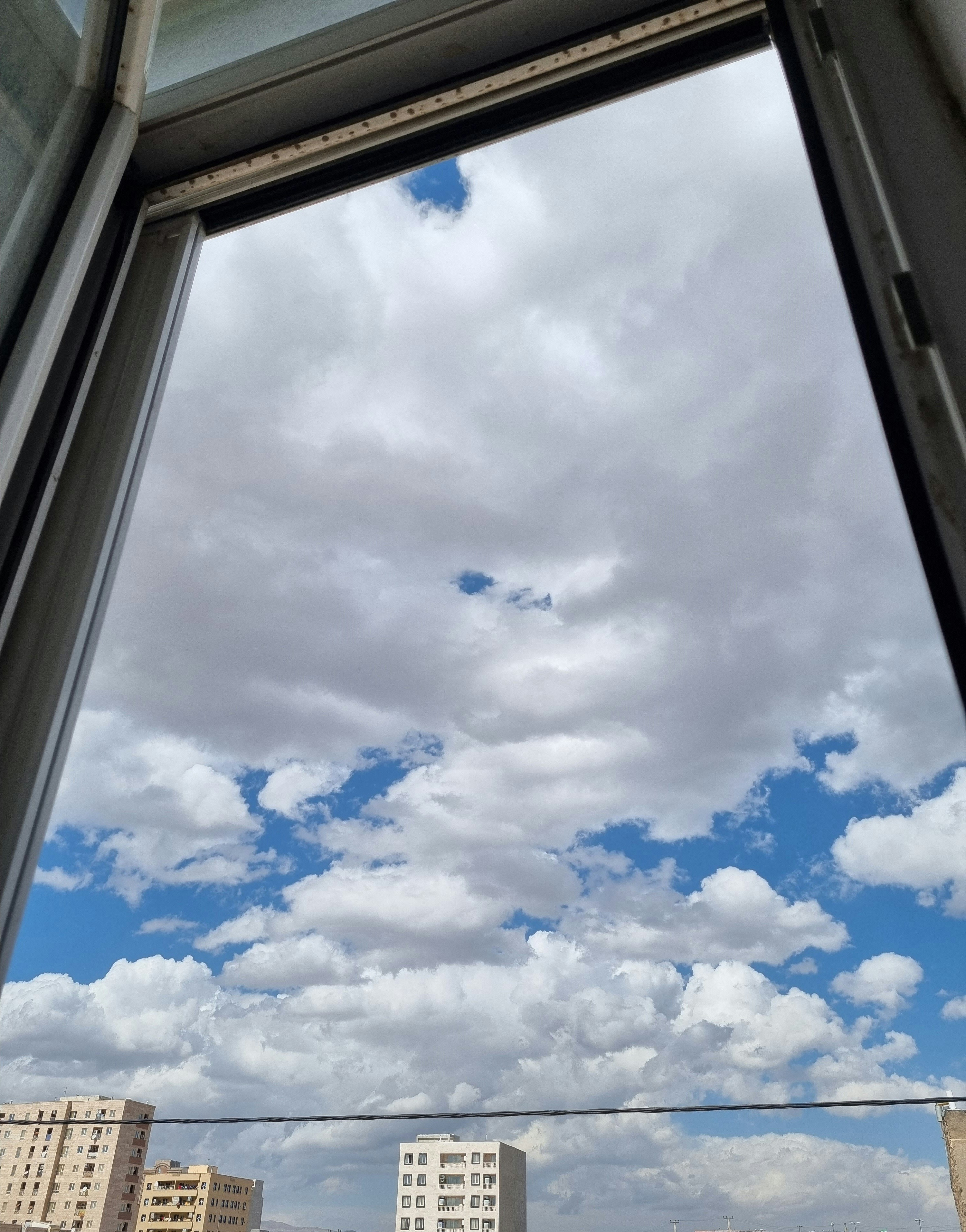 Framed Sky Over a Quiet City: Clouds Through a Narrow Window
