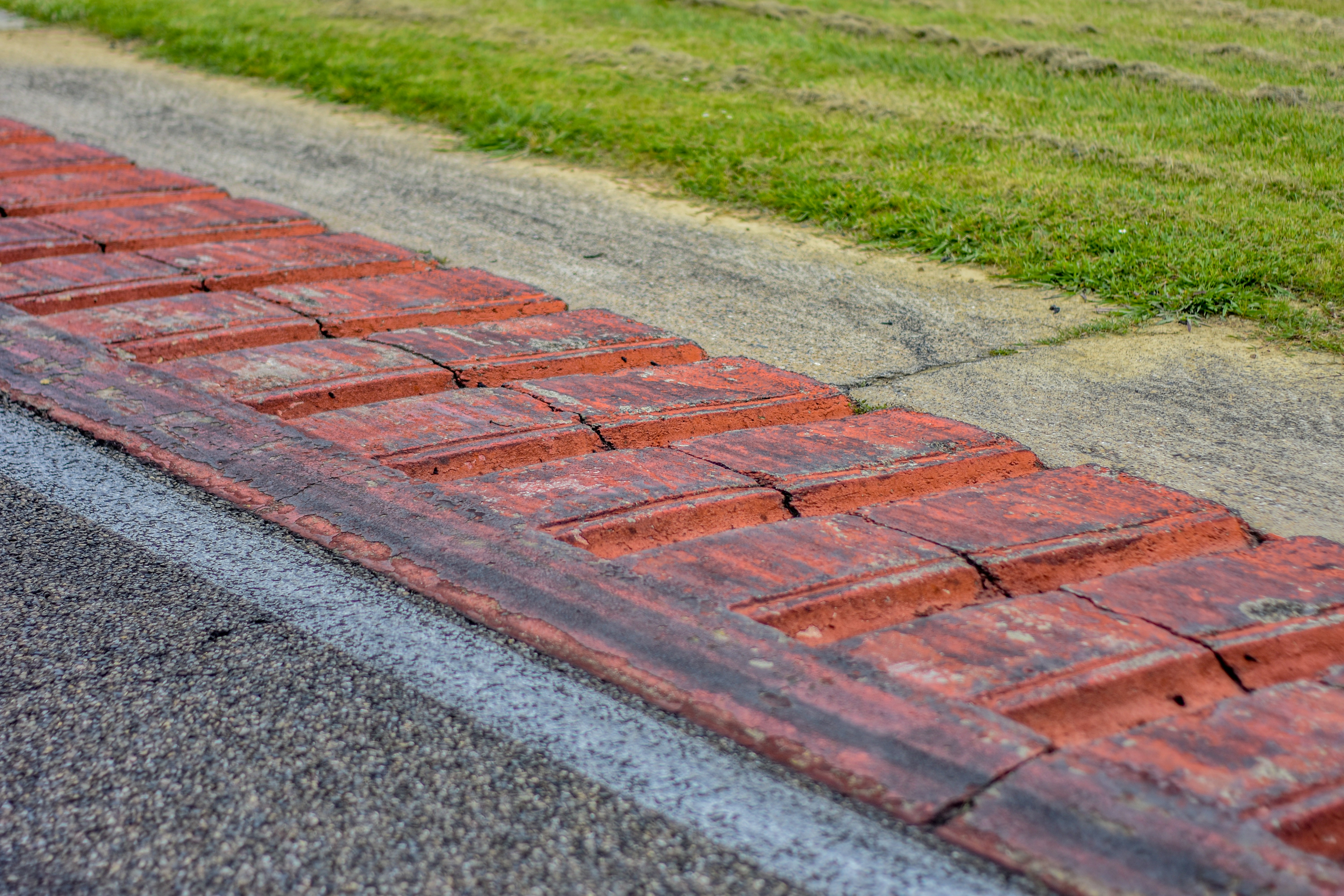 Red brick curb alongside a grassy verge at a racing circuit.