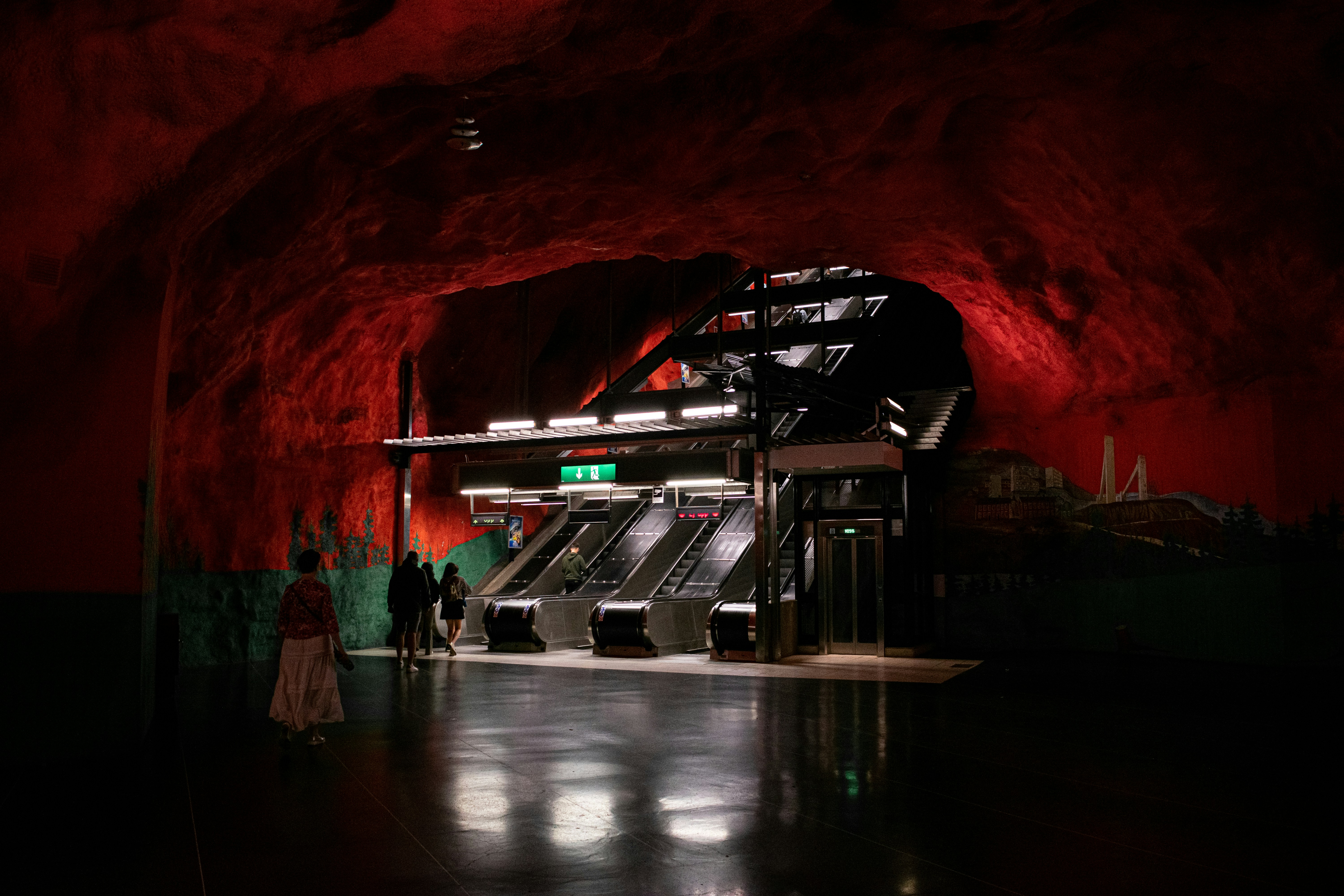 Crimson Cavern Transit: Escalators Ascend Beneath a Red Rock Cathedral