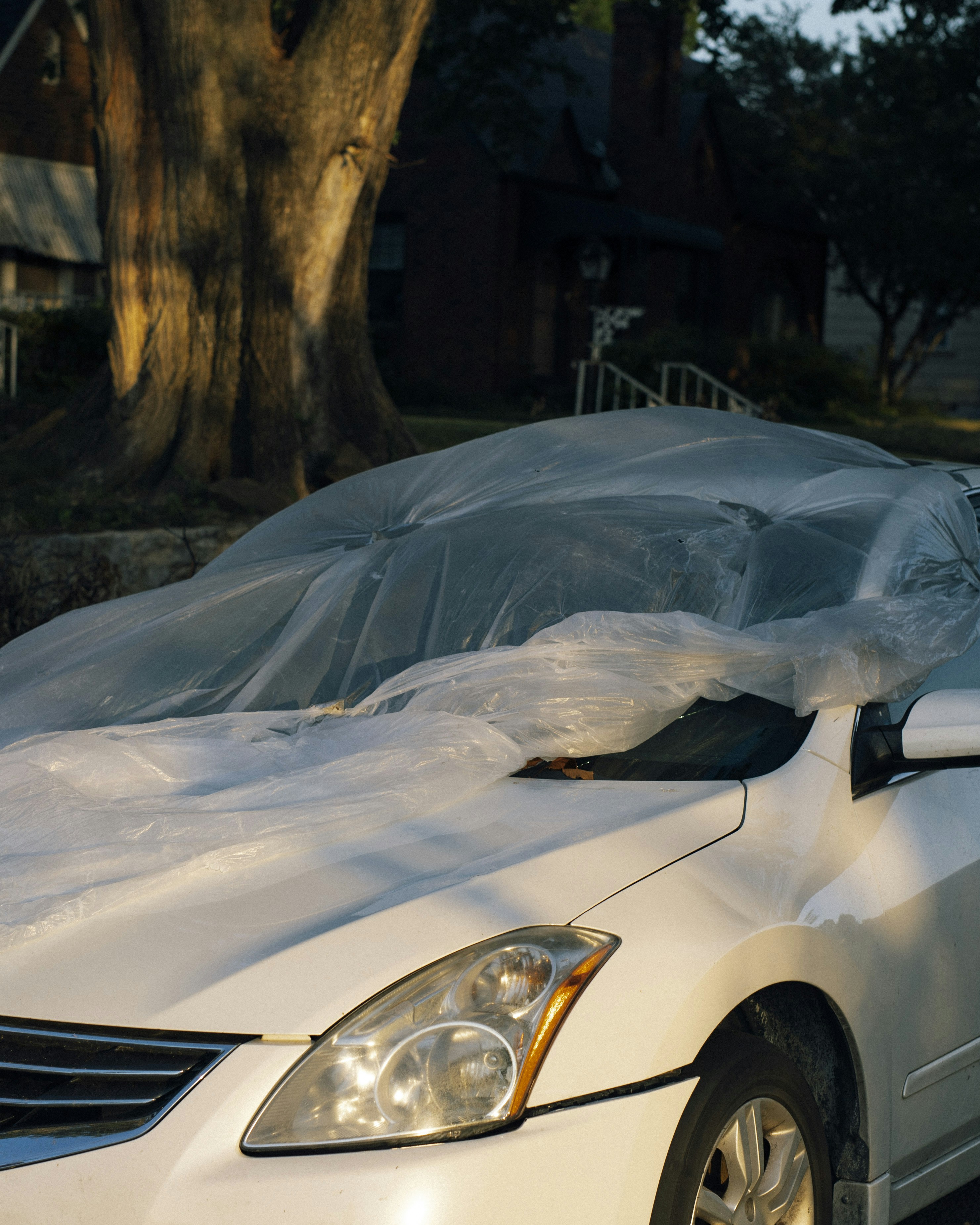 Plastic-Sheeted White Sedan in a Quiet Suburban Dusk