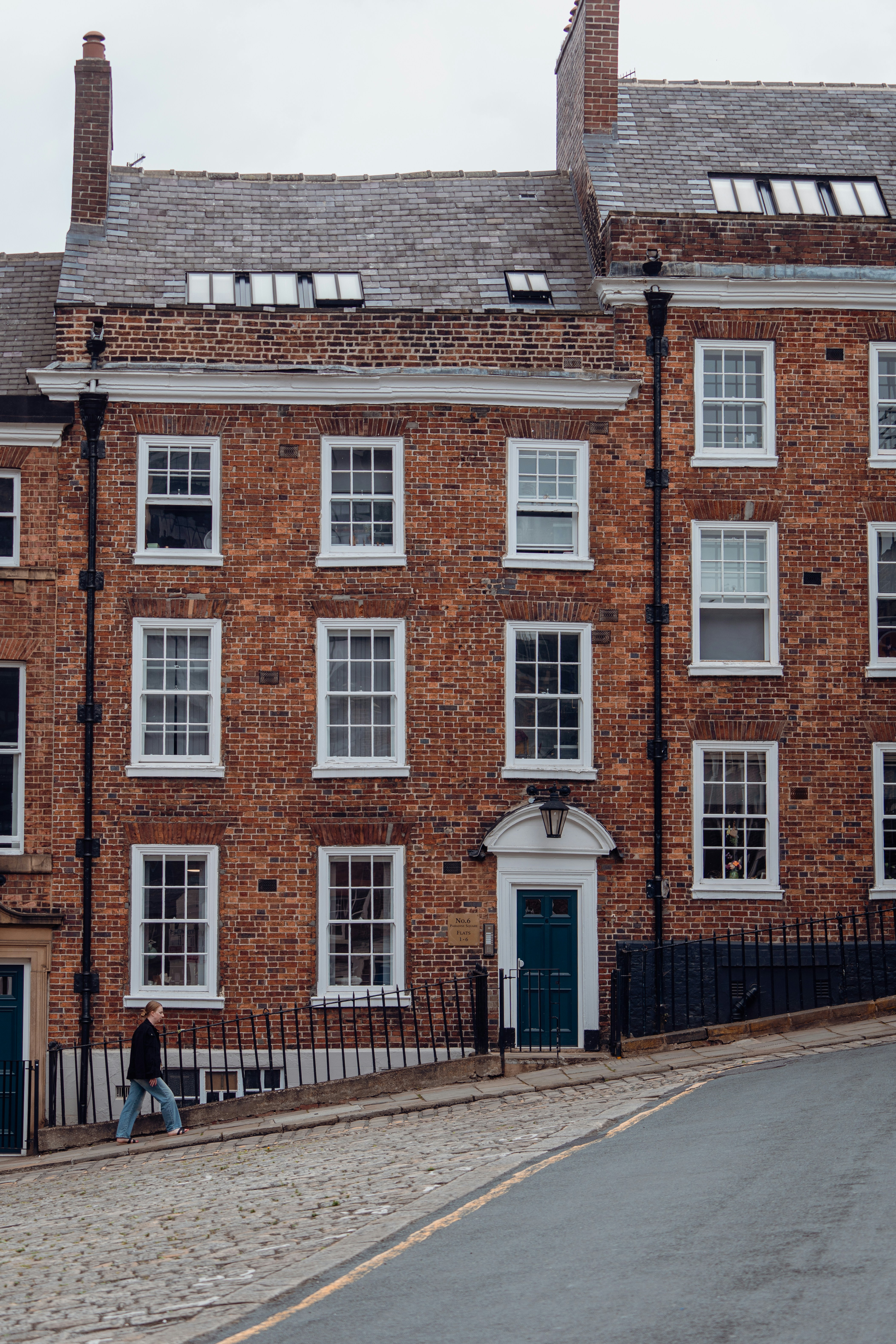 A red brick building with white windows and a blue door photo – Free ...
