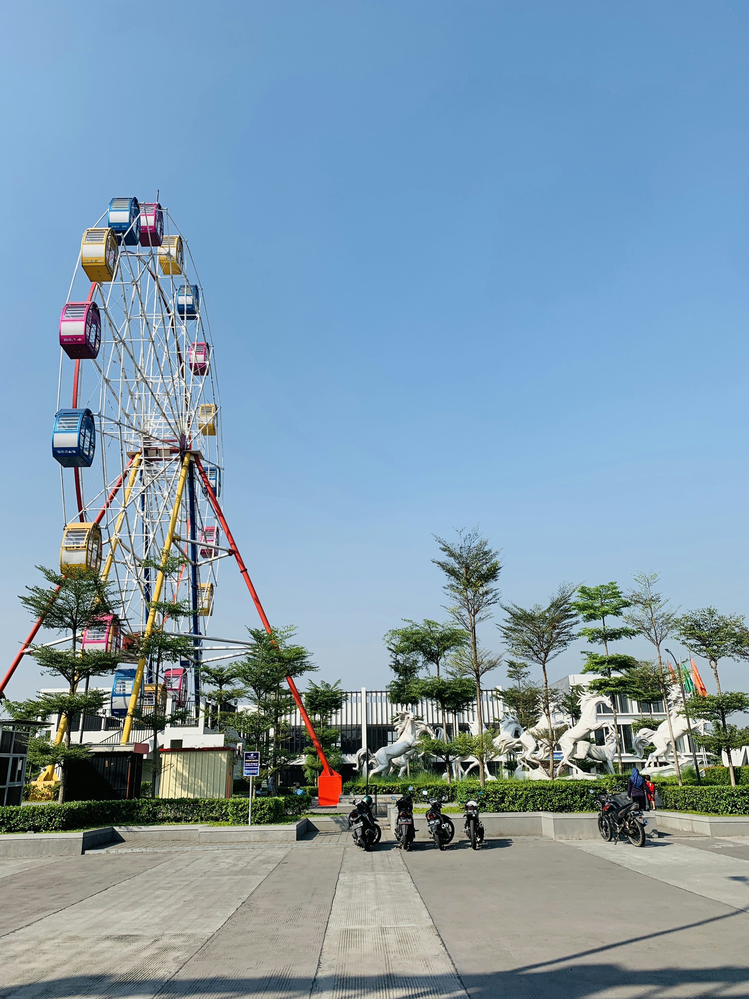 Sunlit Ferris Wheel: A Colorful Landmark Over a Quiet Plaza