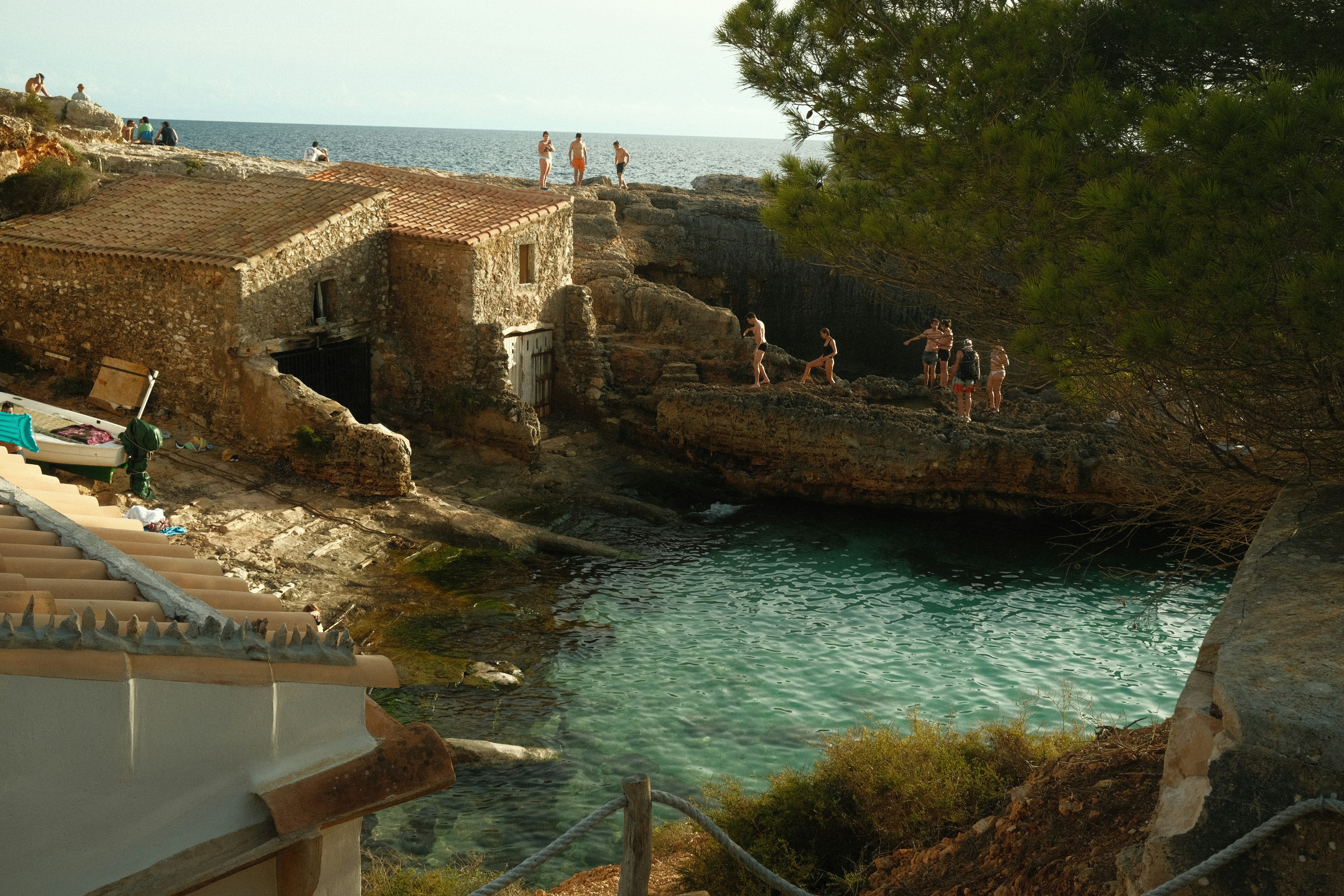 A group of people standing on top of a cliff next to a body of water photo – Free Mallorca Image ...