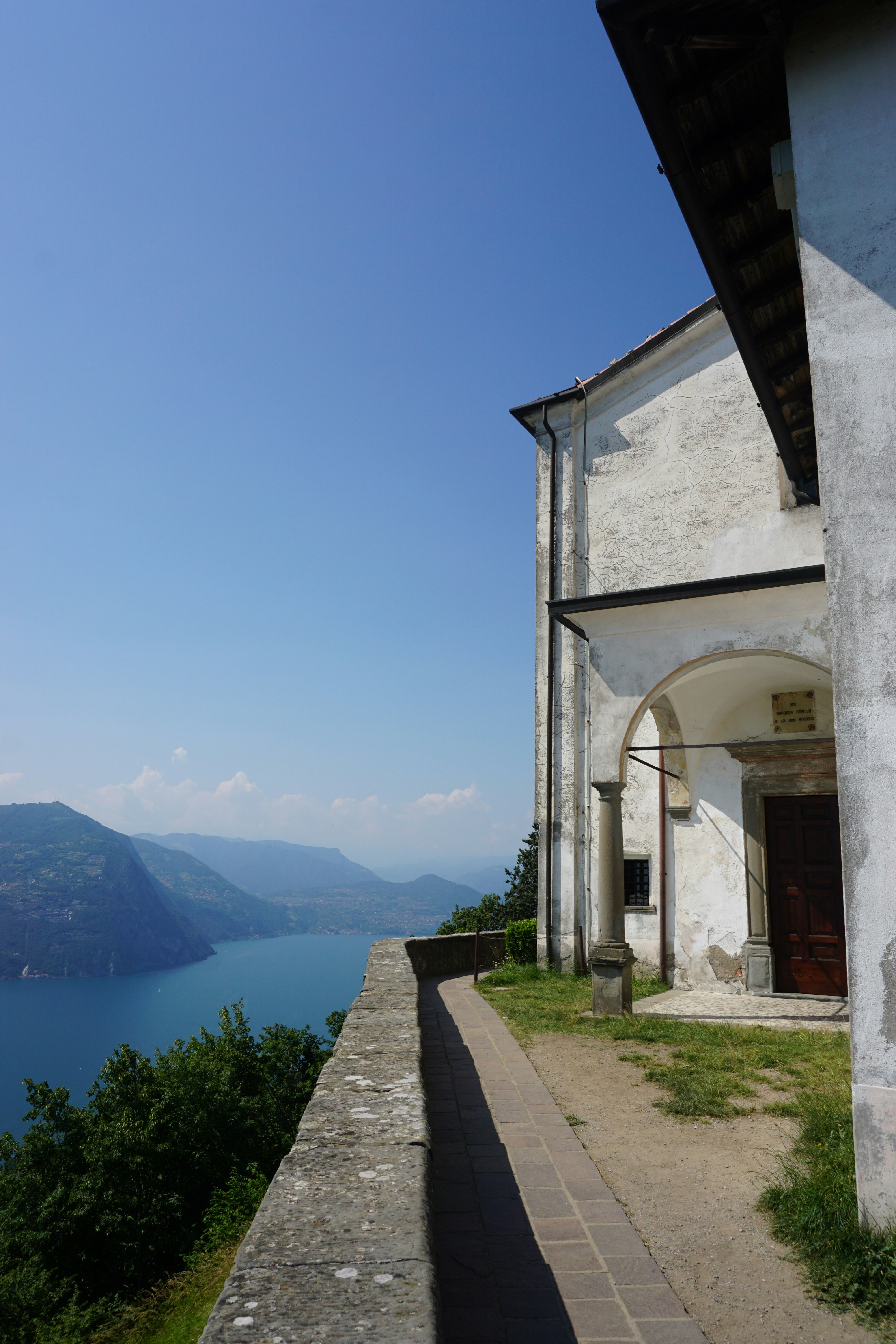 A cliffside monastery overlook by a sunlit lake