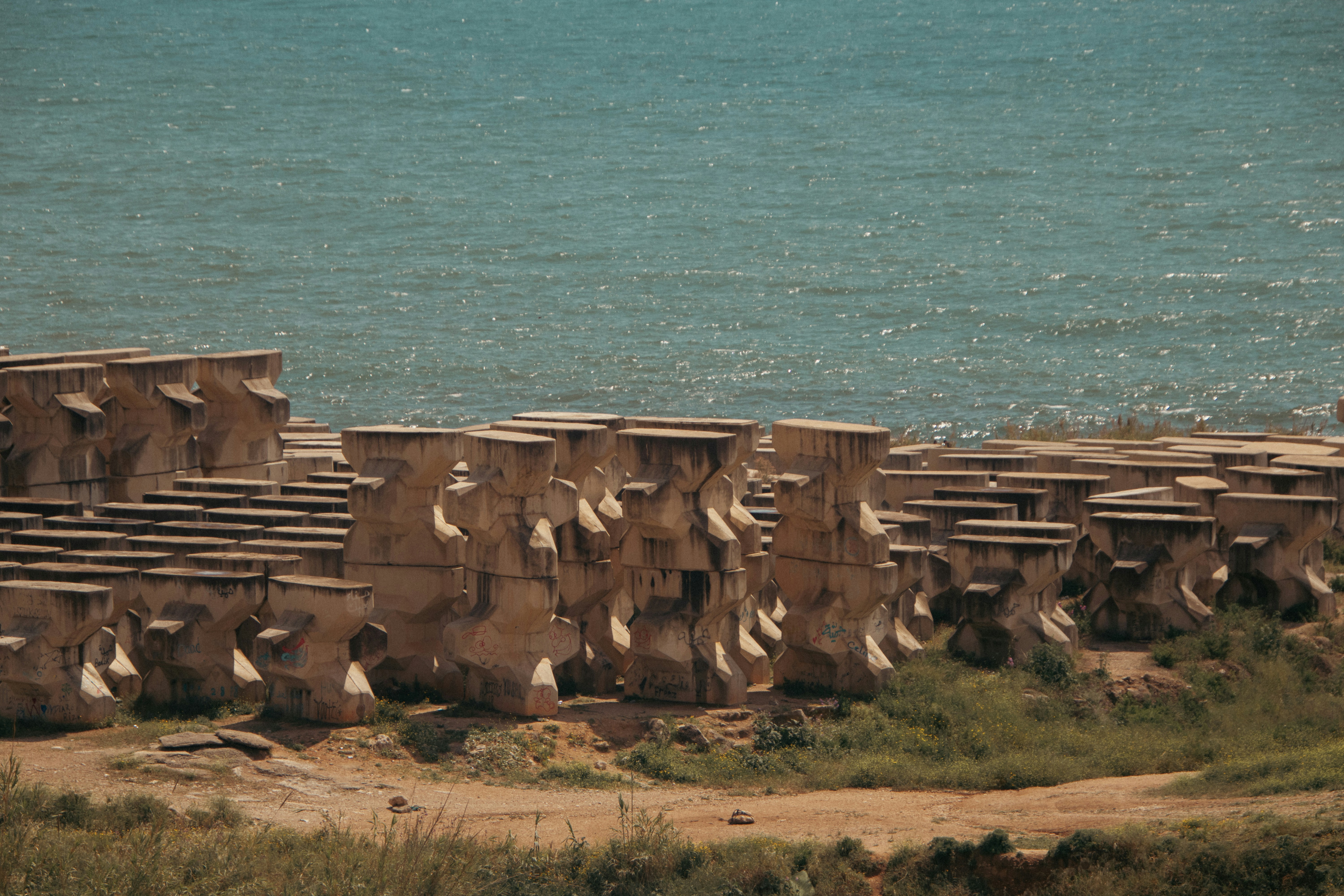 Abstract coastal structures rise from the earth, merging with the sea in a striking display of architecture and nature.
