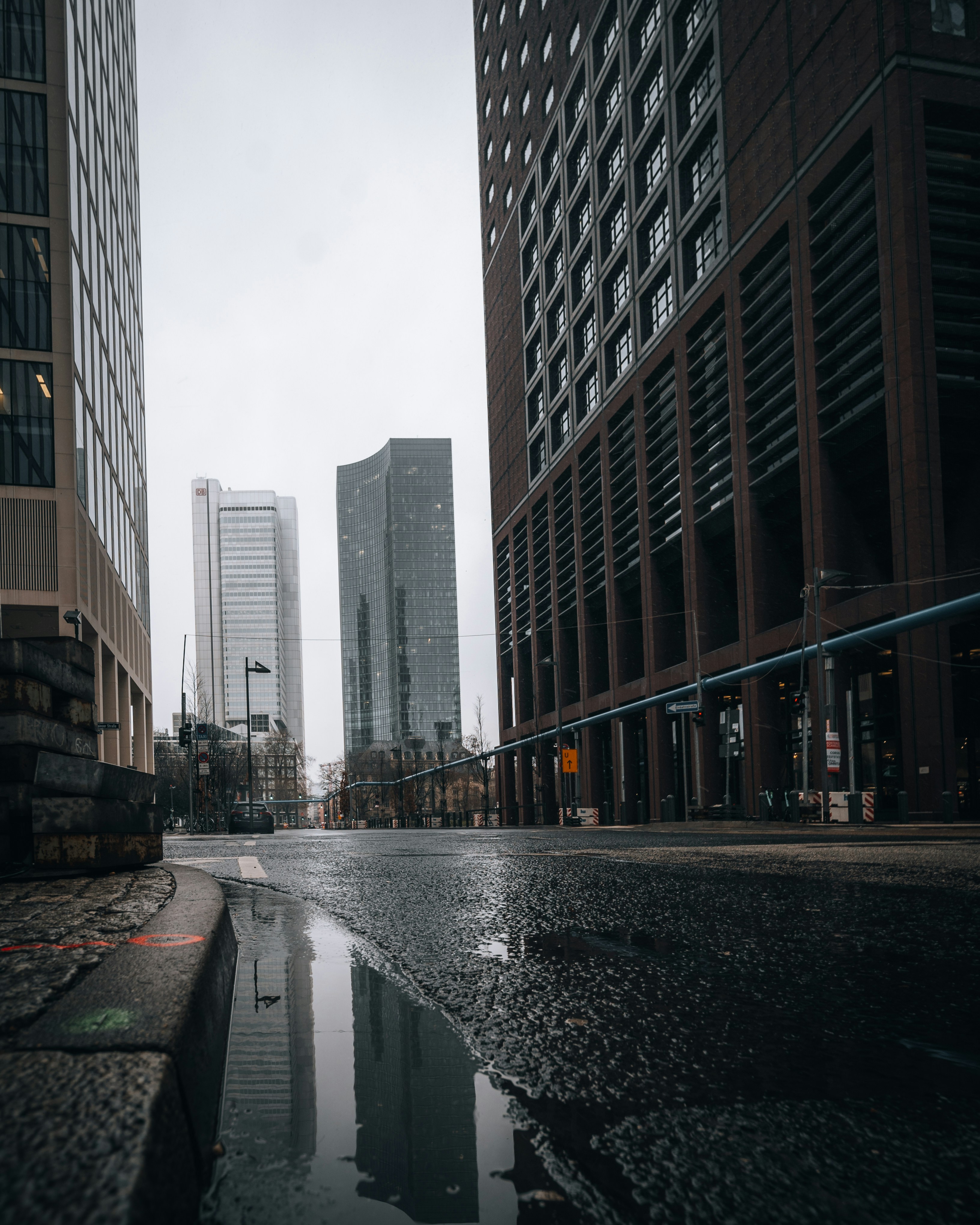 A wet city street with tall buildings in the background photo – Free ...