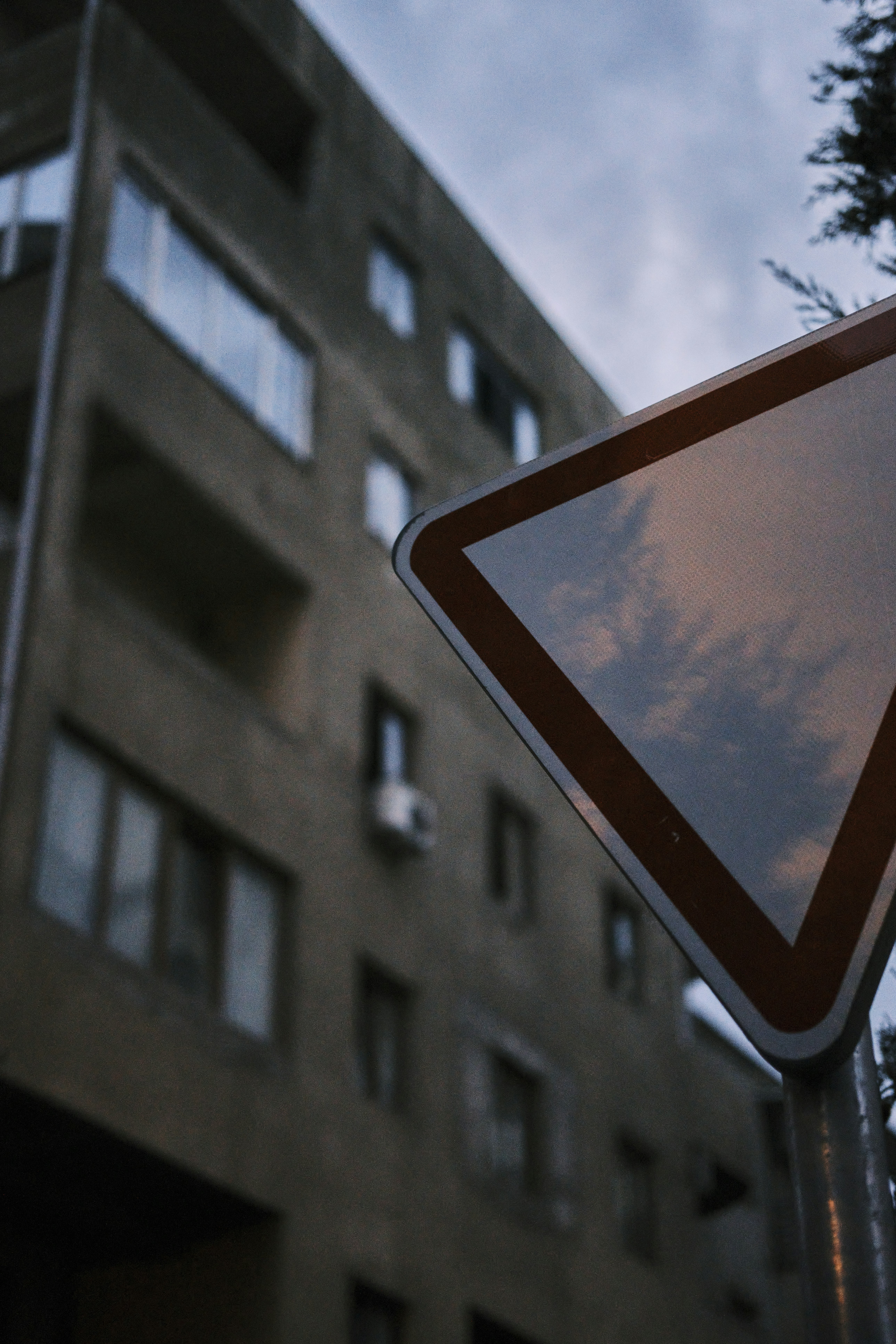 Tilted Yield Sign Reflects Sky Over the Urban Facade