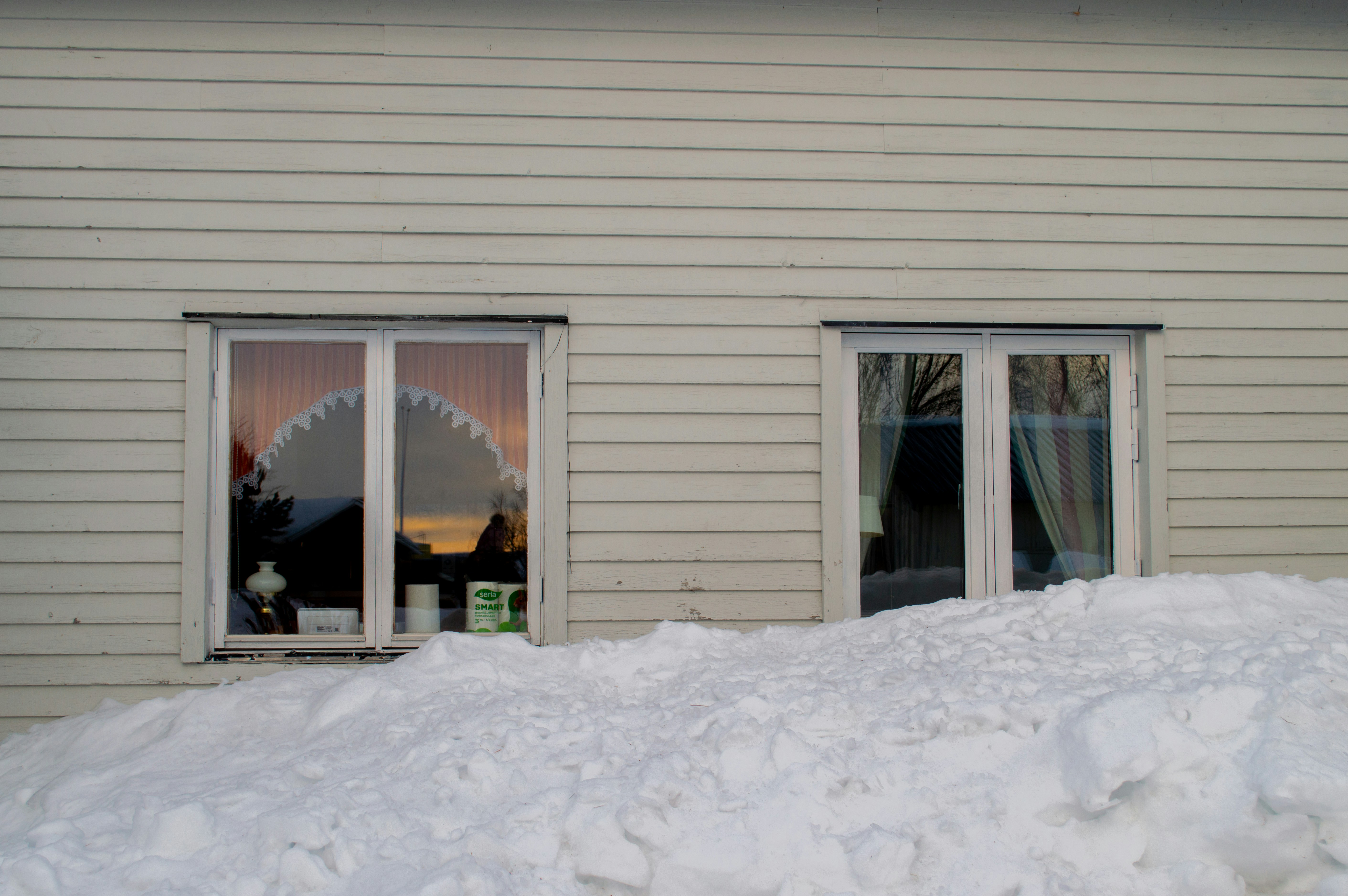 A white house with two windows and a pile of snow photo – Free Exterior ...