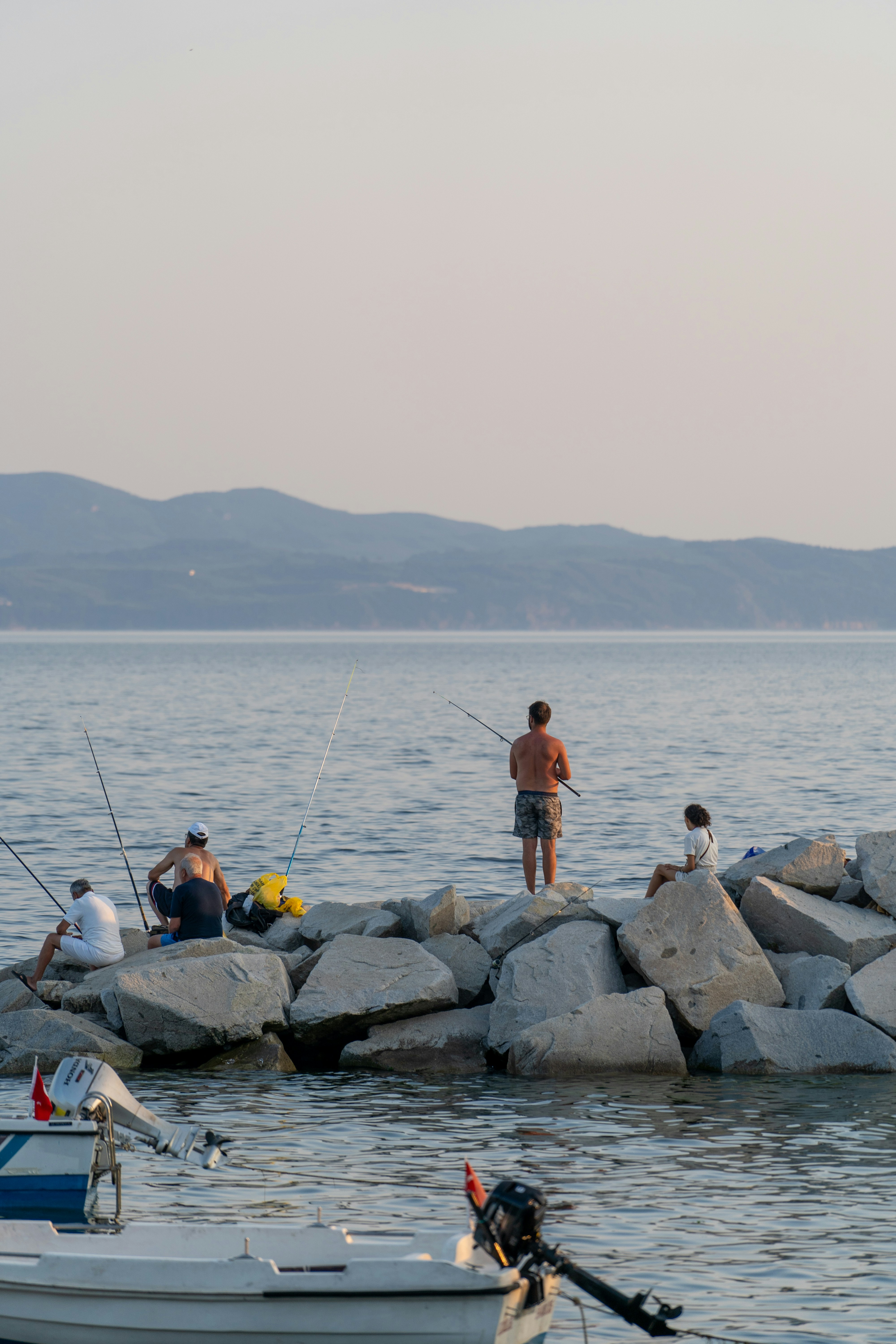 A group of people fishing off of rocks in the water photo – Free ...