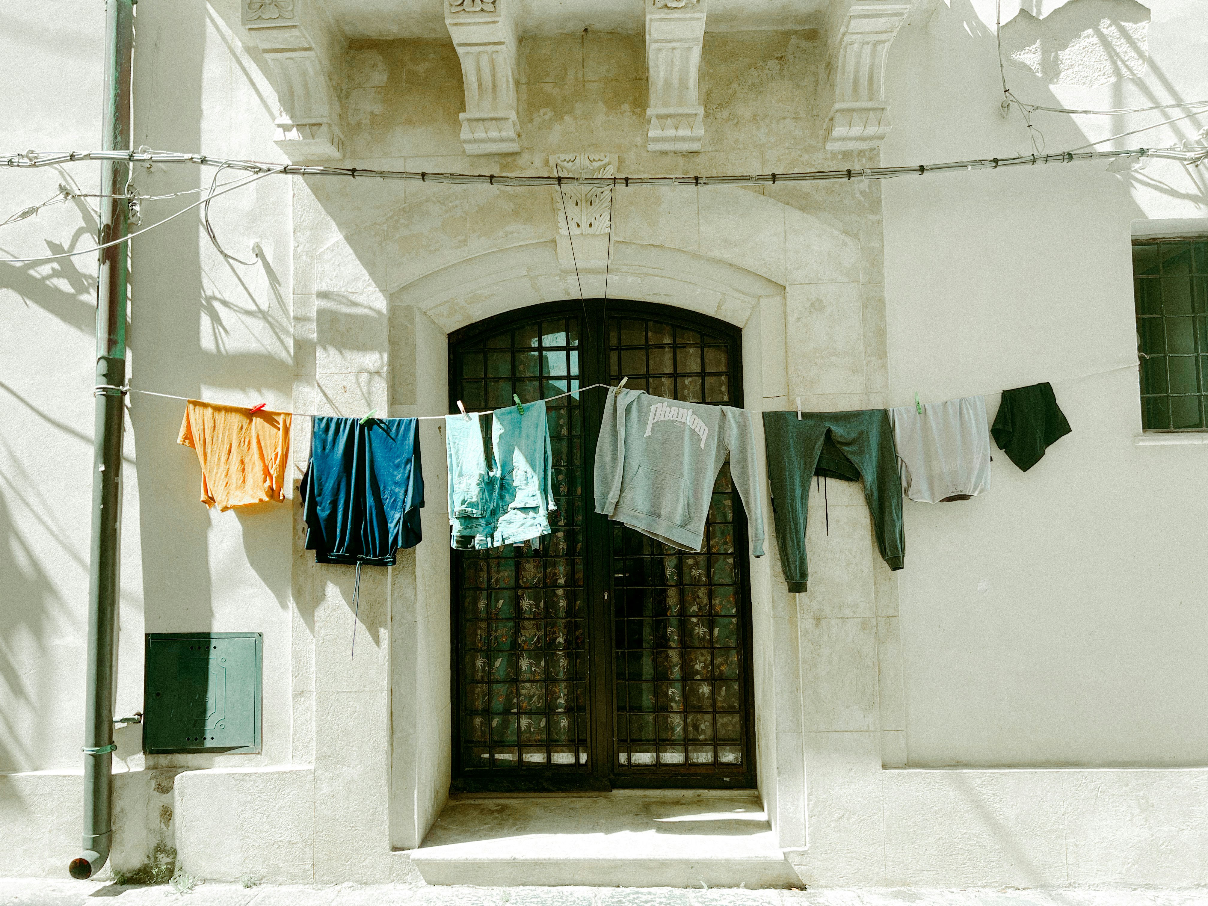 Clothesline adorned with colorful garments strung between two walls, highlighting the simplicity of daily routines in a charming urban setting.
