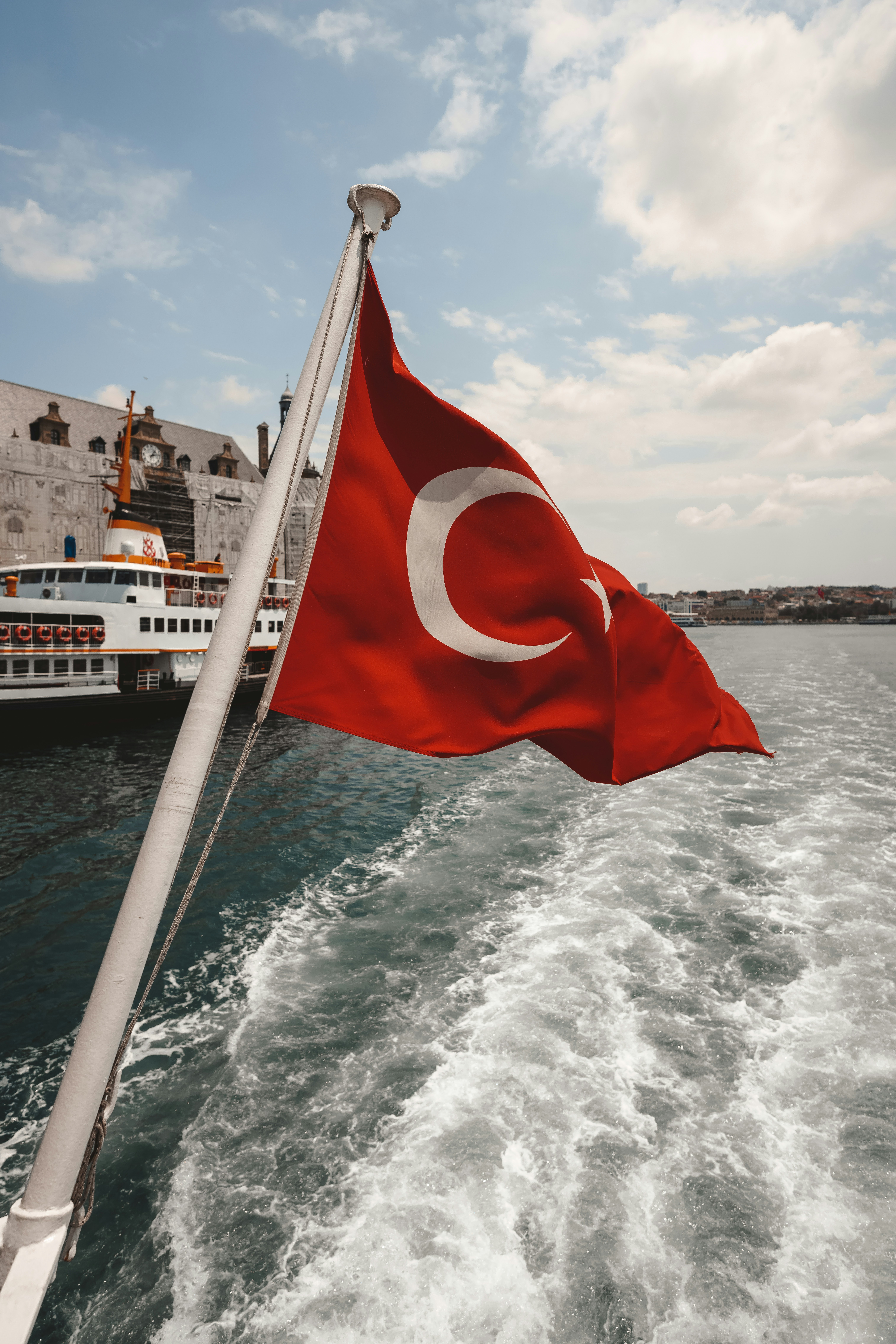 Bow Flag over Turquoise Wake: A Turkish Harbor Moment
