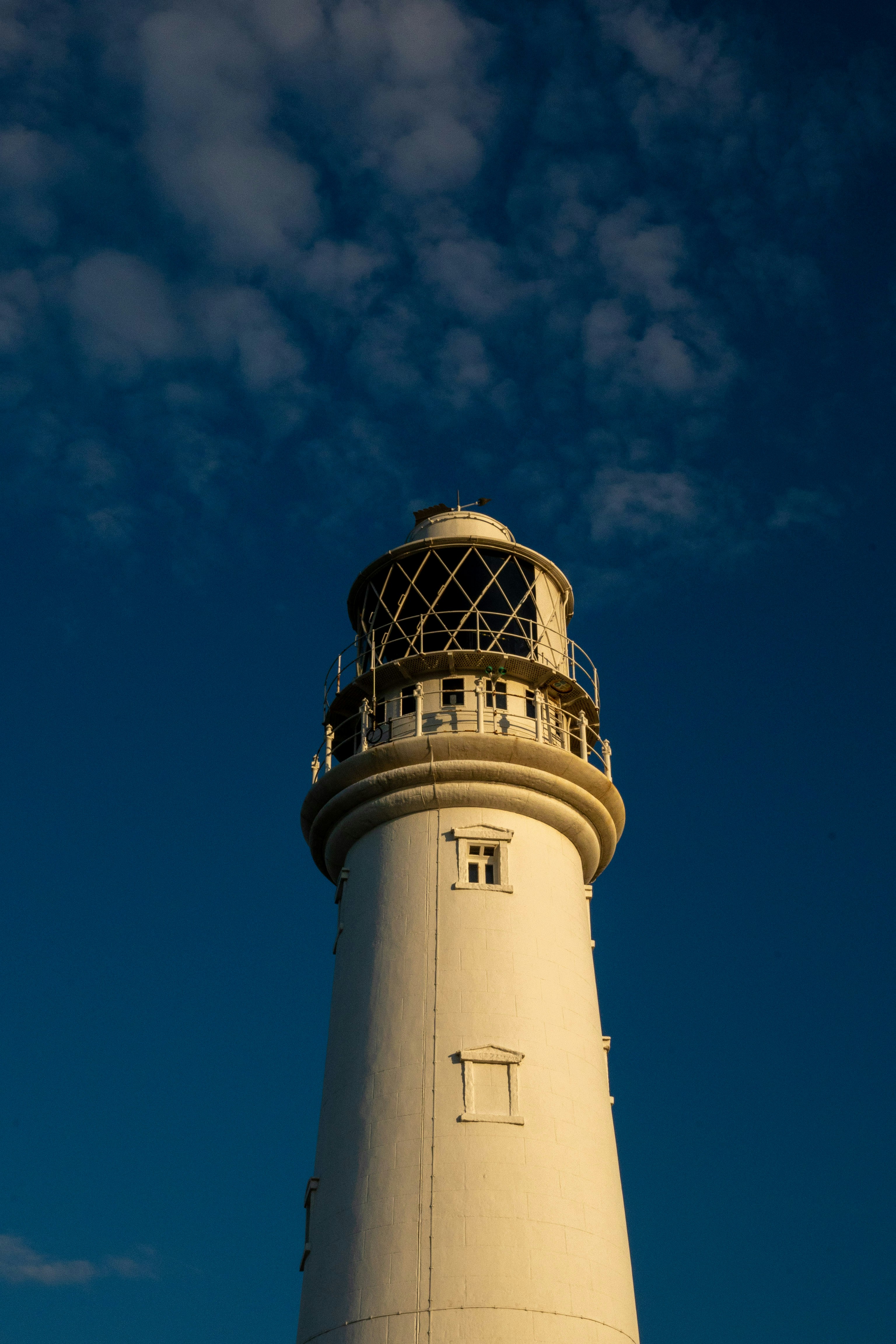 A white lighthouse with a blue sky in the background photo – Free ...