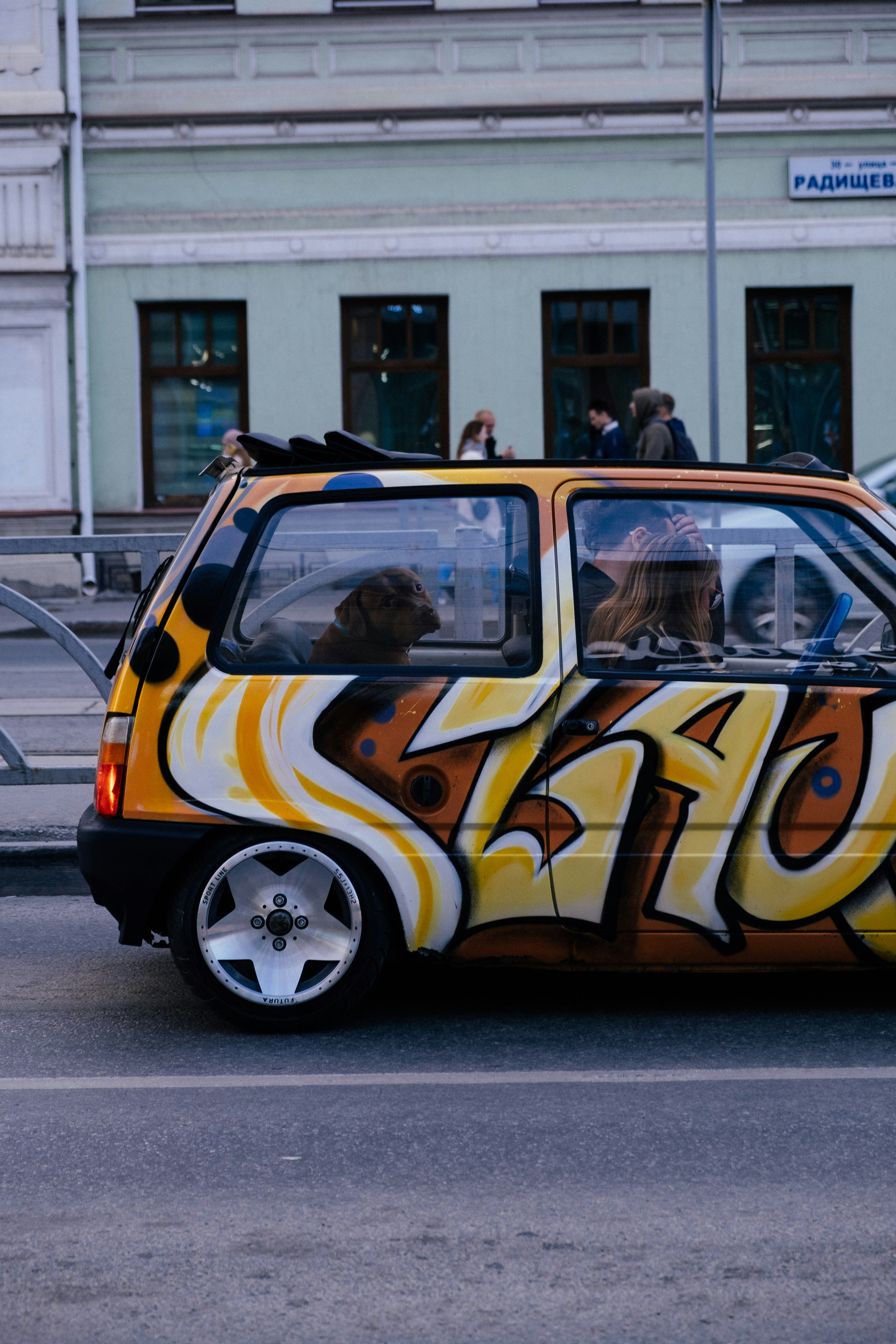 Dog Peeks Through a Graffiti-Wrapped City Van