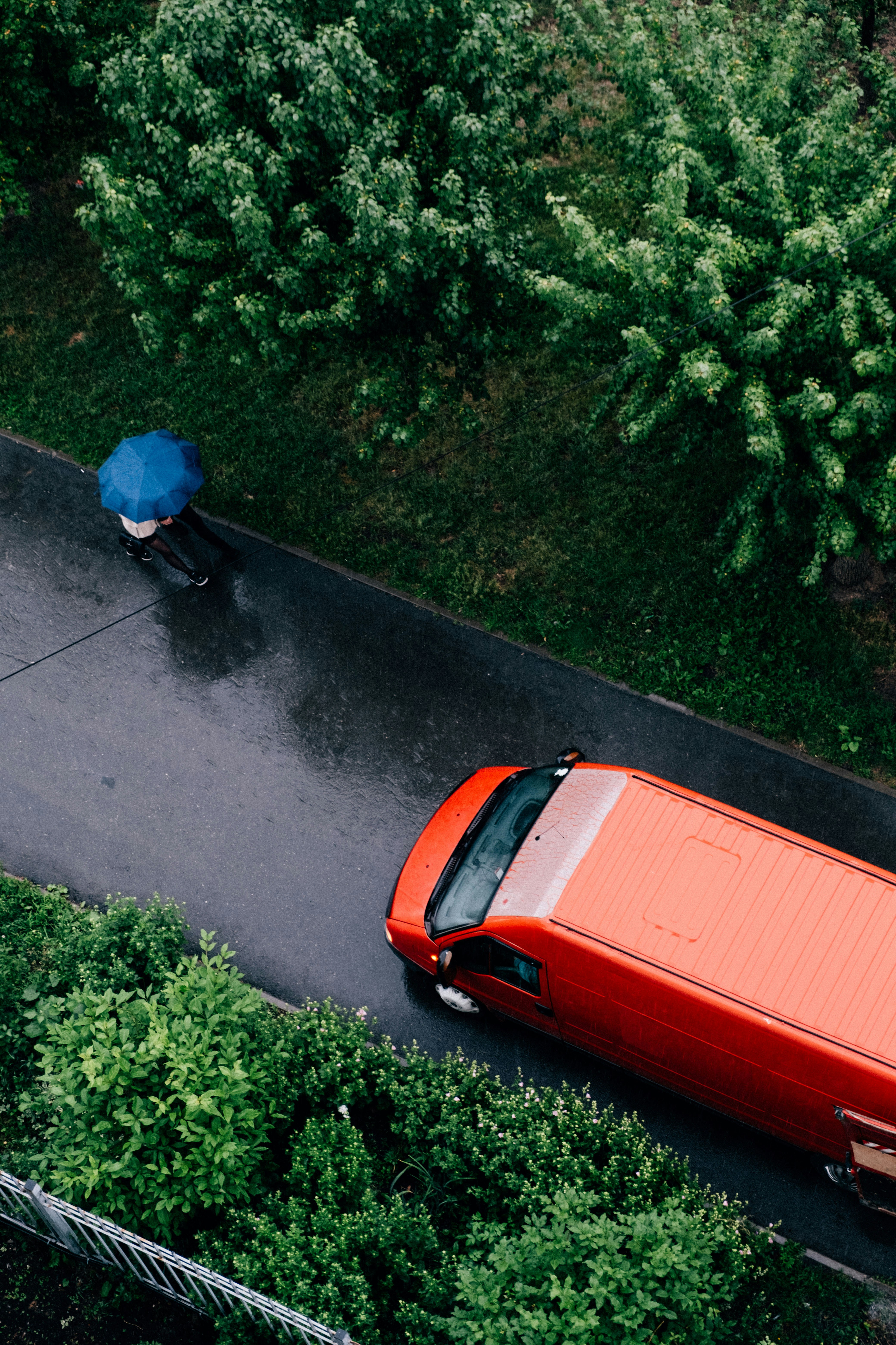 Blue Umbrella, Red Van: A Rain-Washed Street in a Green Frame