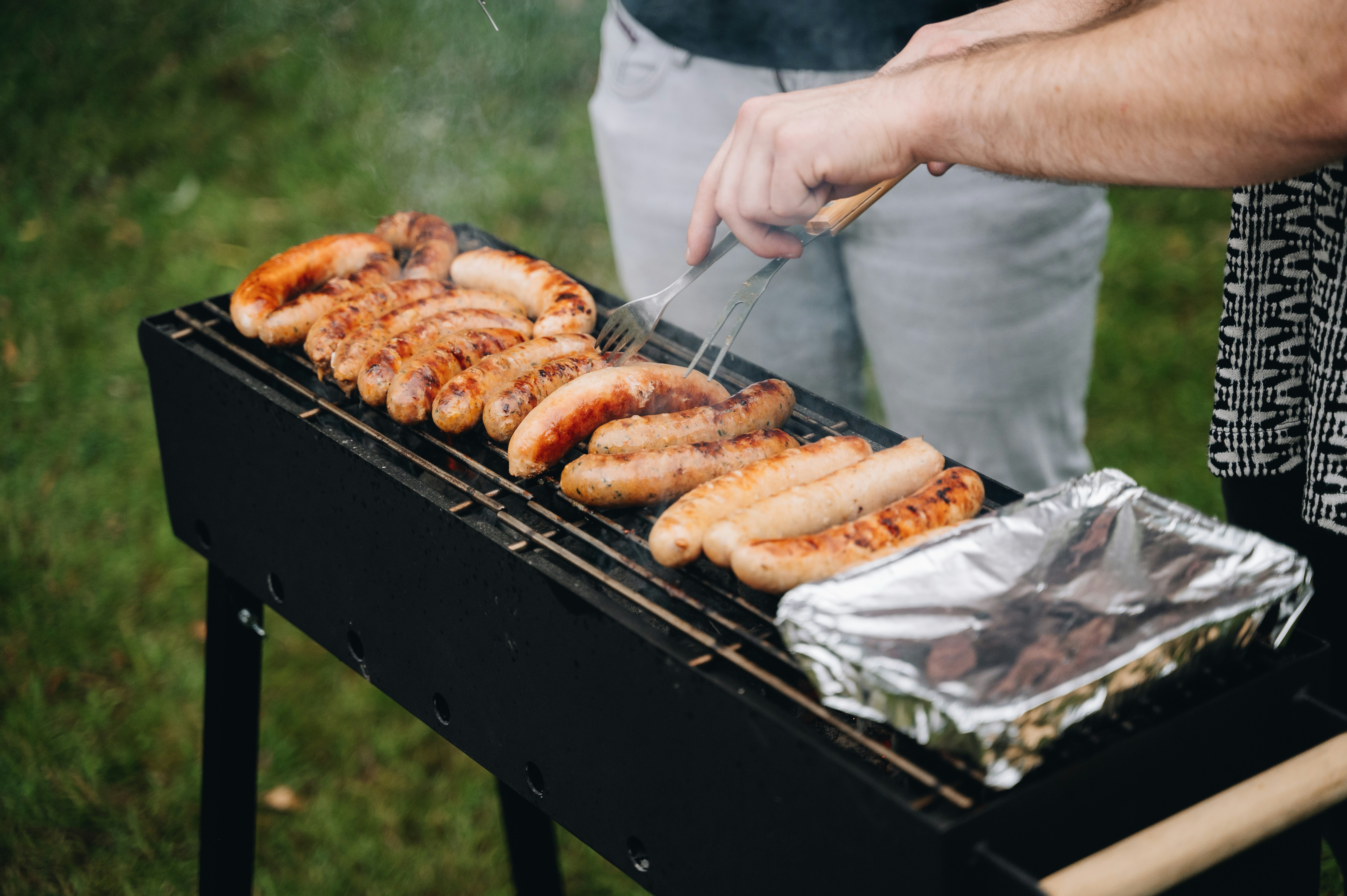 A man grilling hot dogs and sausages on a grill photo – Free Bbq Image ...