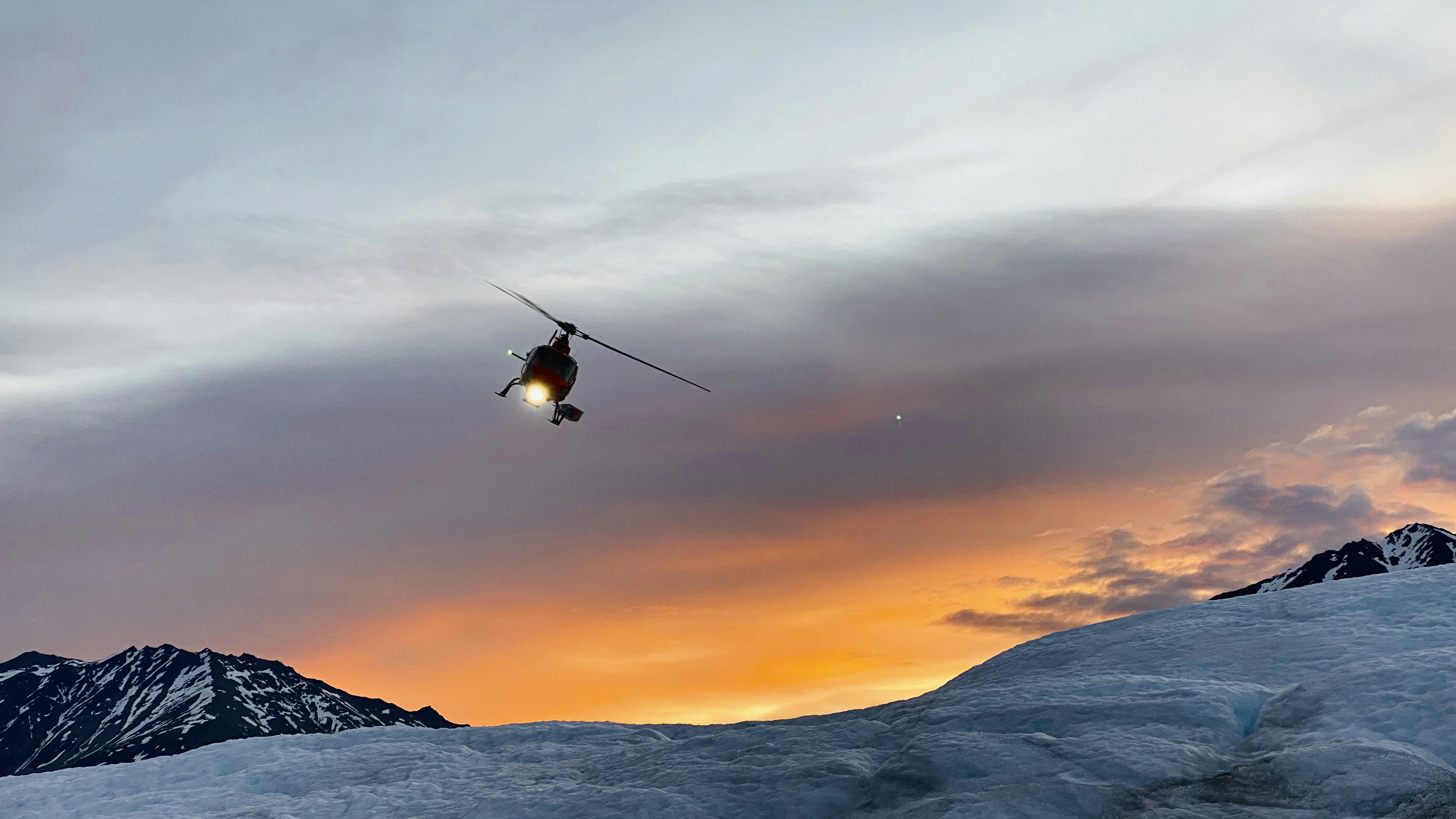A helicopter flying over a snow covered mountain photo – Free Alaska ...