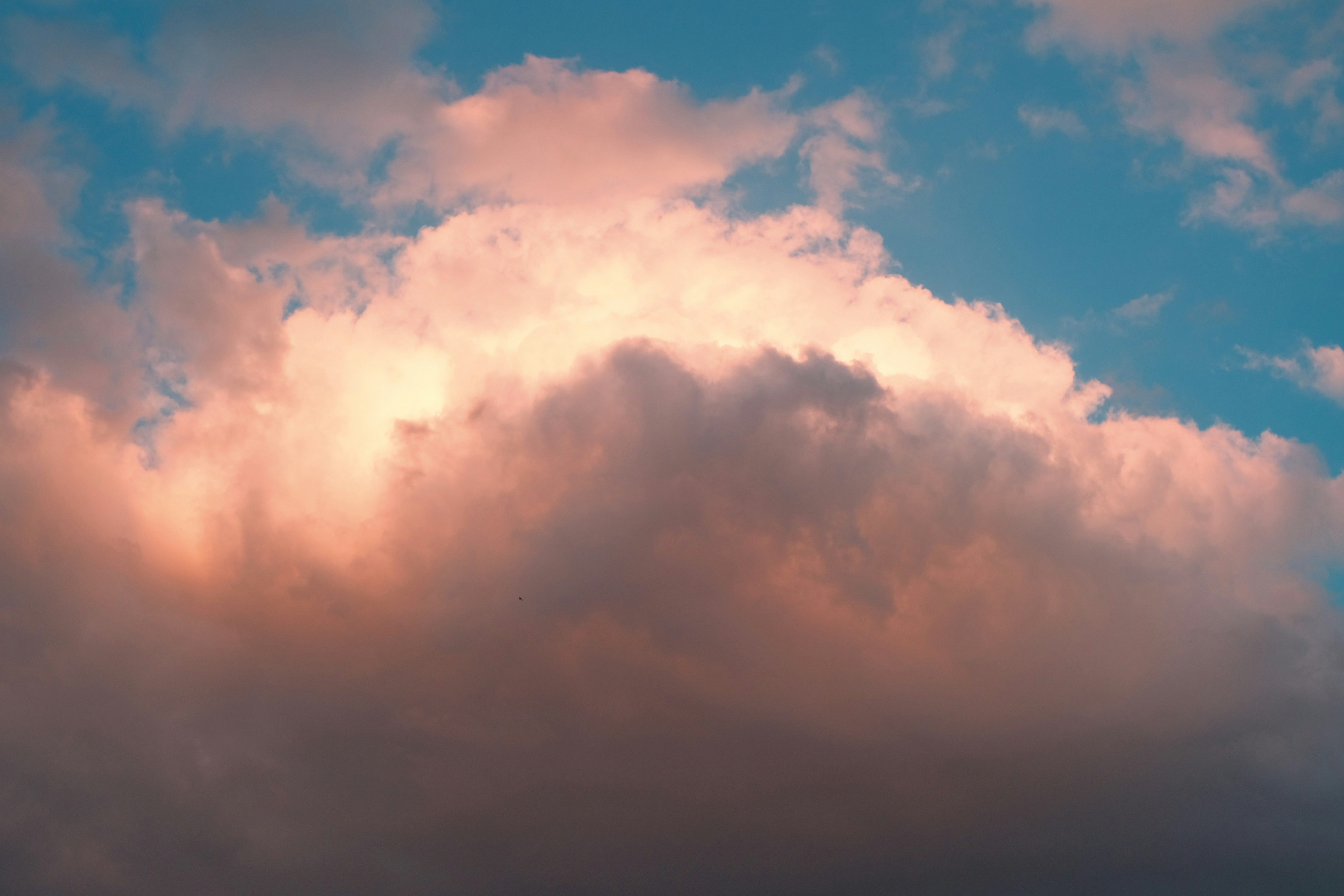 Airplane gliding through a vast expanse of fluffy clouds under a clear blue sky.