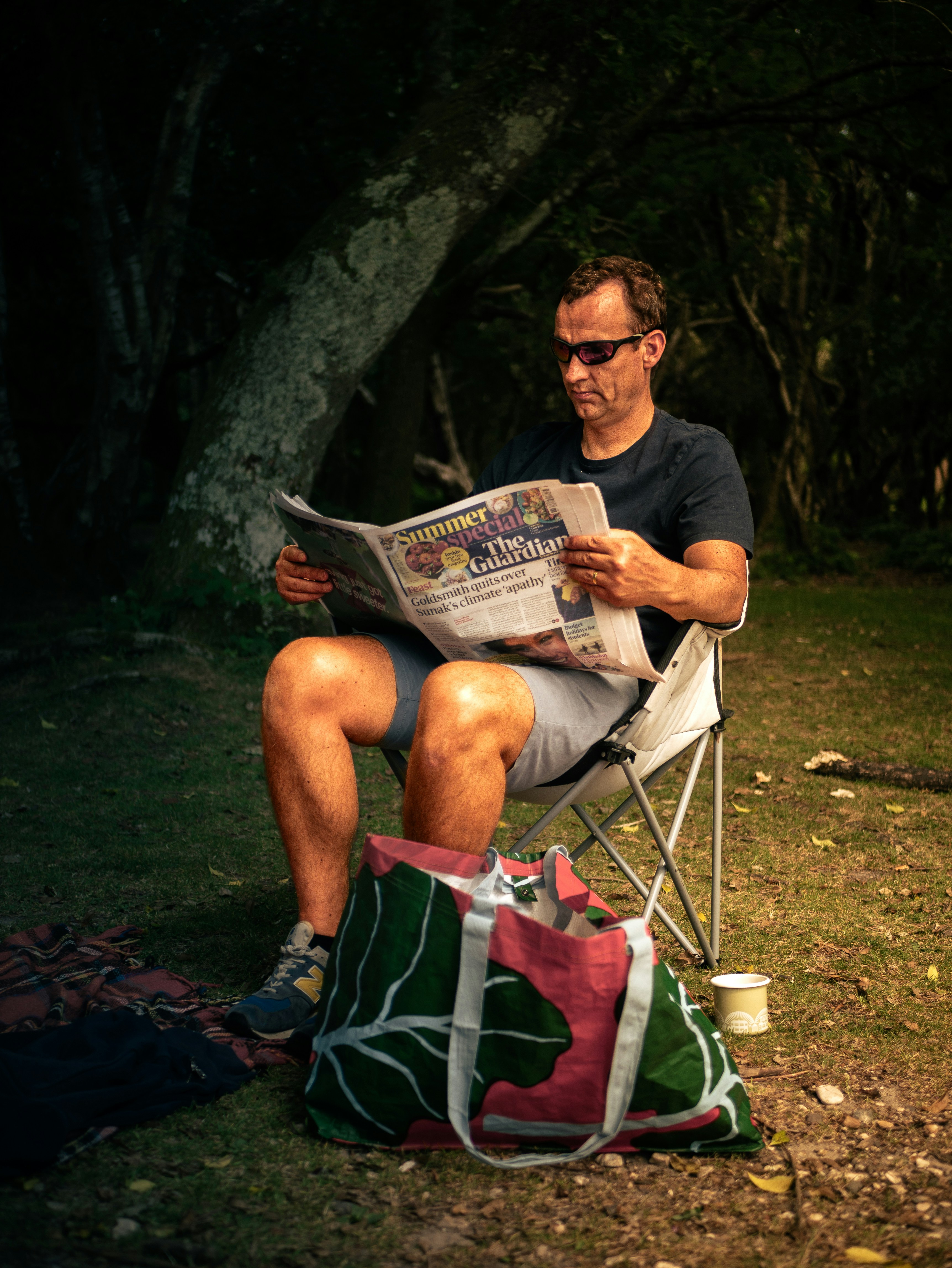 Forest Pause: The Reader in Sunglasses Finds Focus Under a Canopy