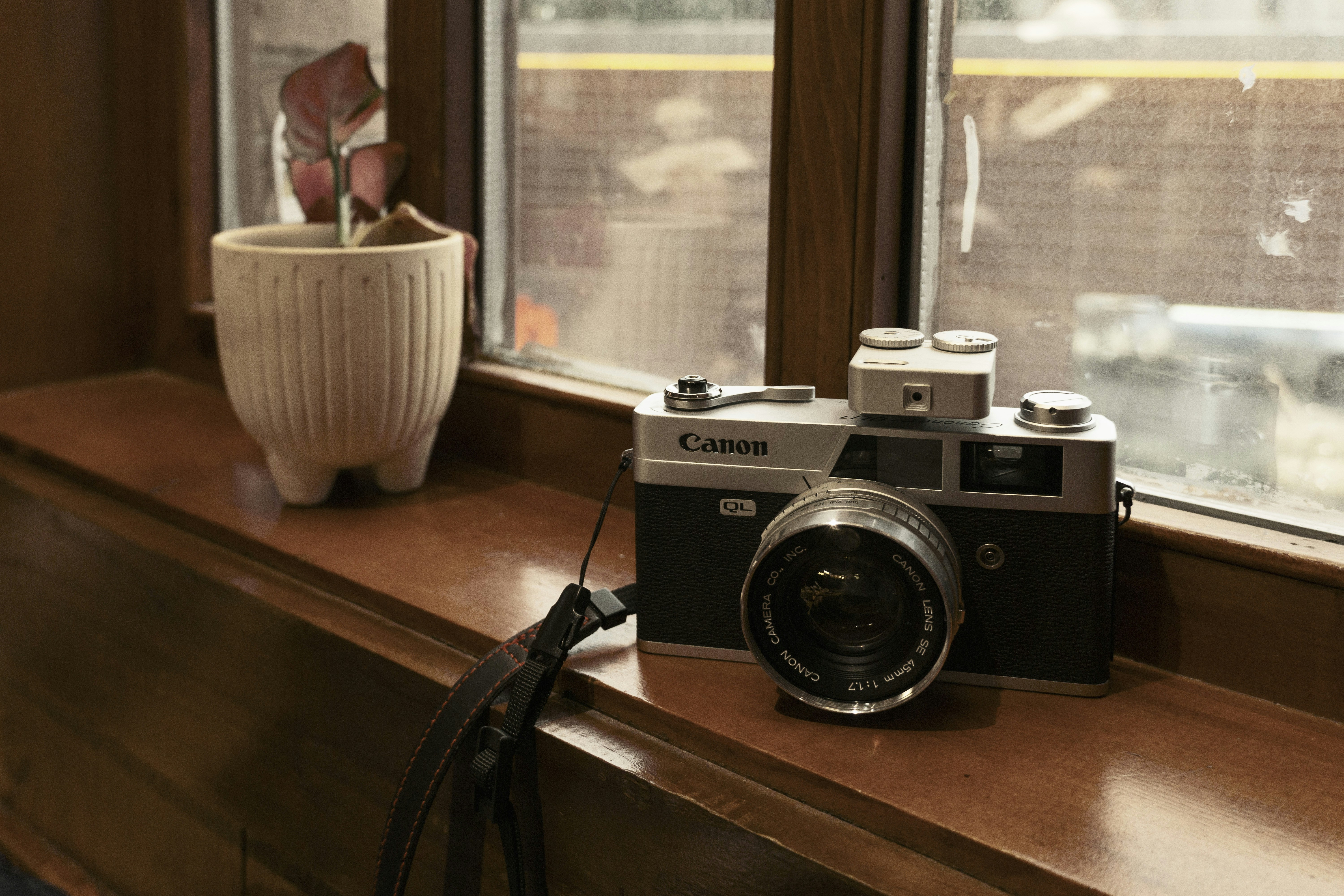 A camera sitting on a window sill next to a potted plant photo – Free ...
