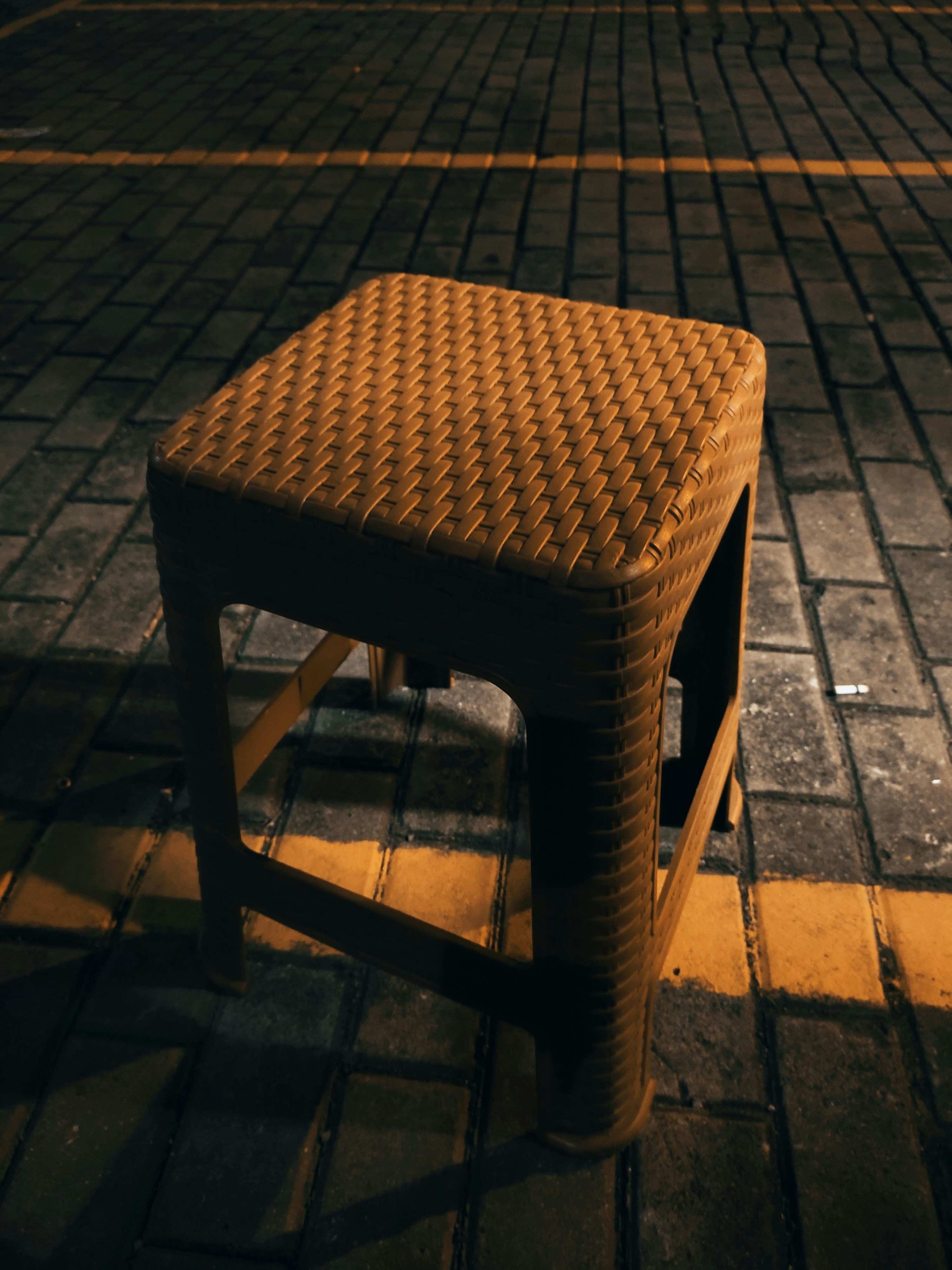 A wicker stool sitting on a sidewalk at night photo – Free Furniture ...