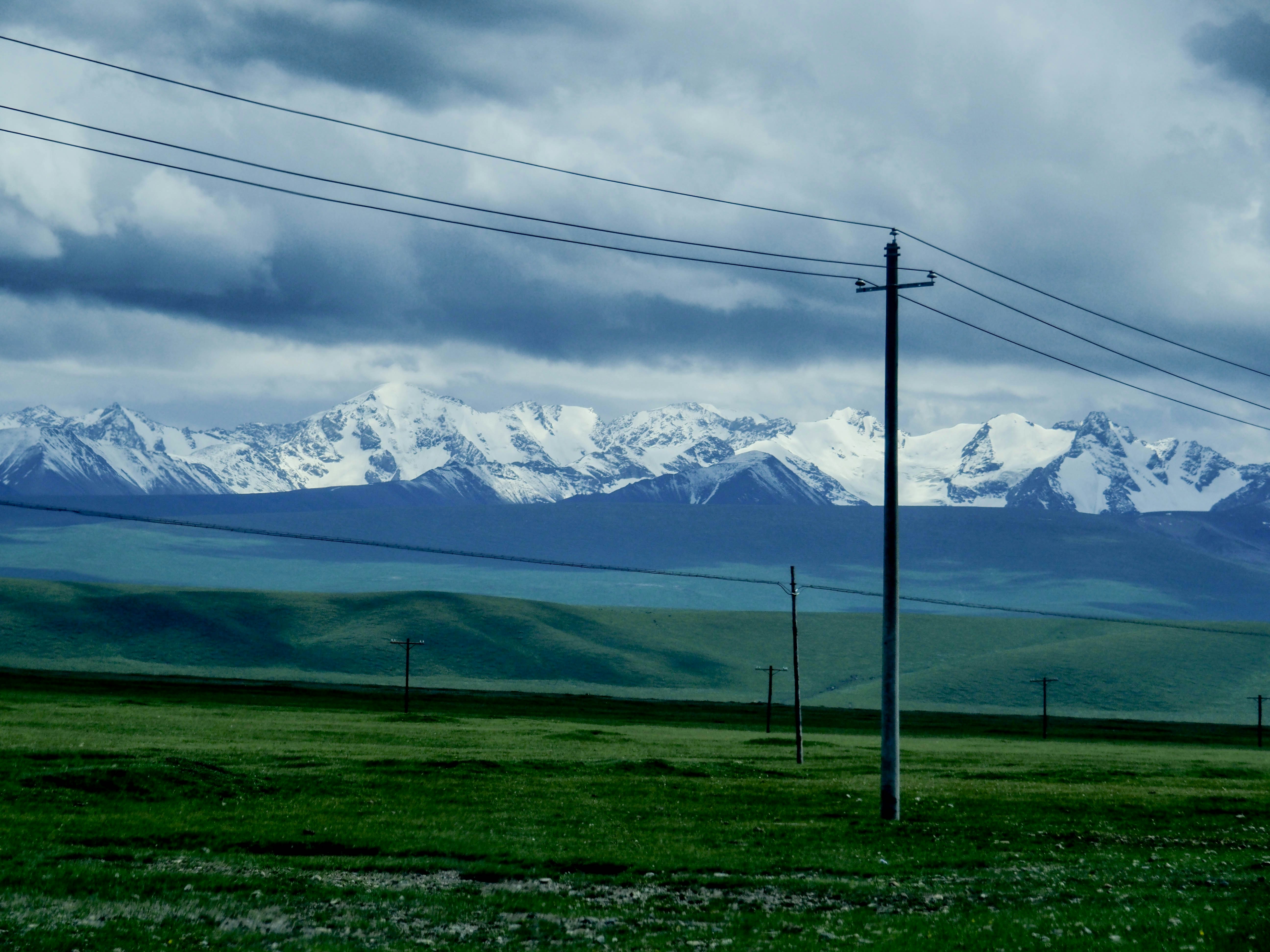 A field with power lines and mountains in the background photo – Free ...