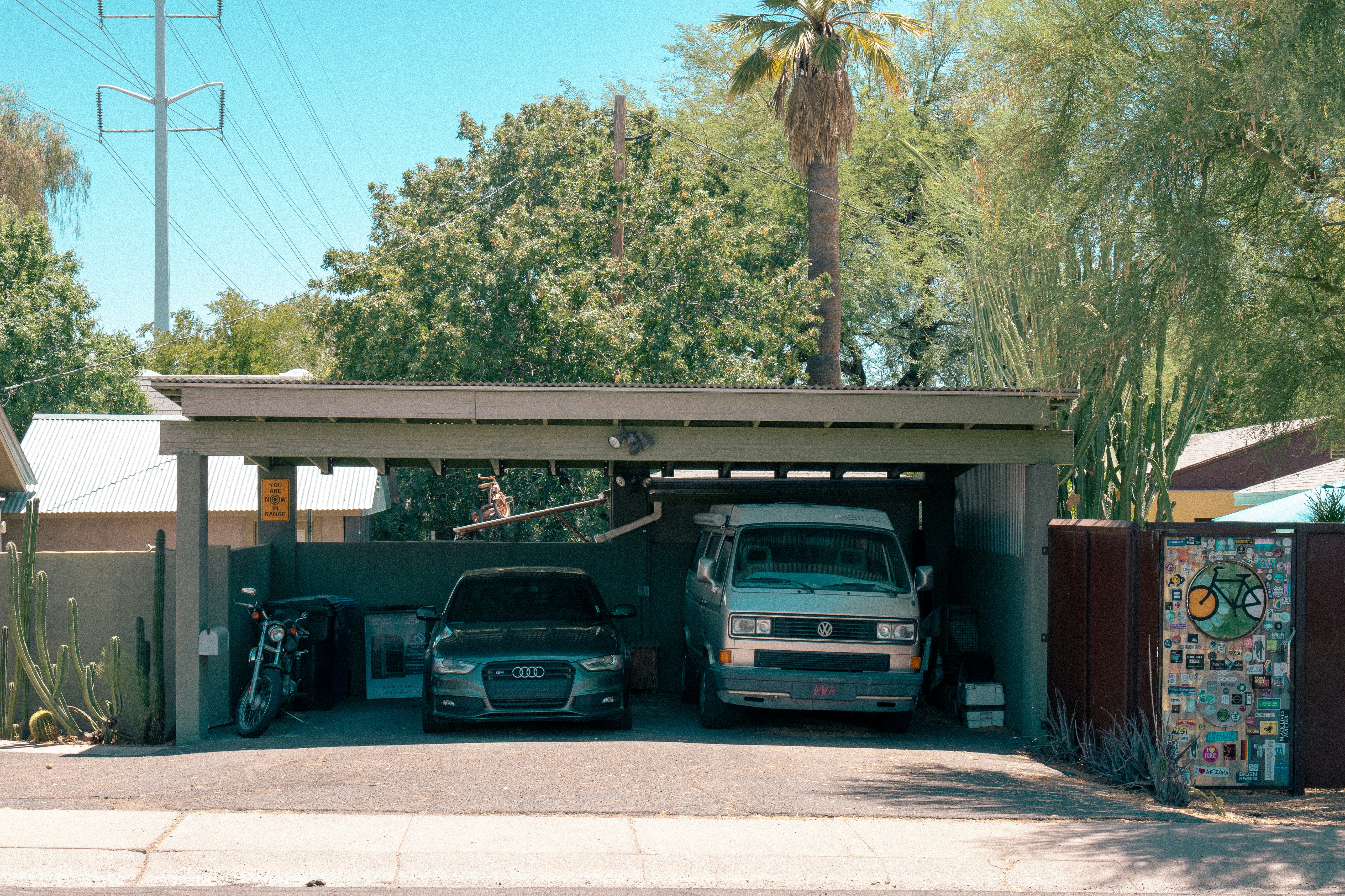 Carport Portrait: A Modest Driveway with a Silver Audi and a Blue Van